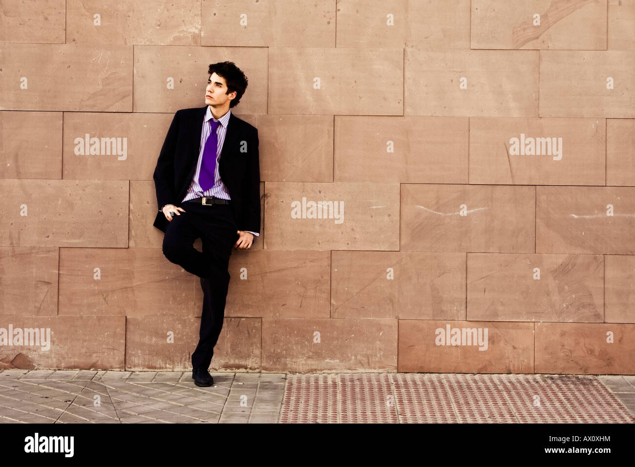 Lone businessman posing on wall Stock Photo - Alamy