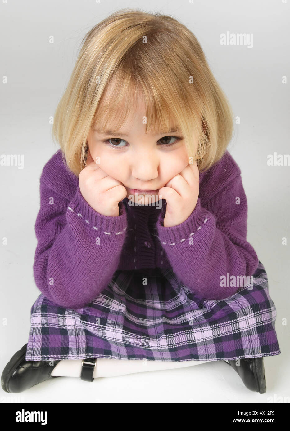 Pouting little girl sitting down Stock Photo - Alamy