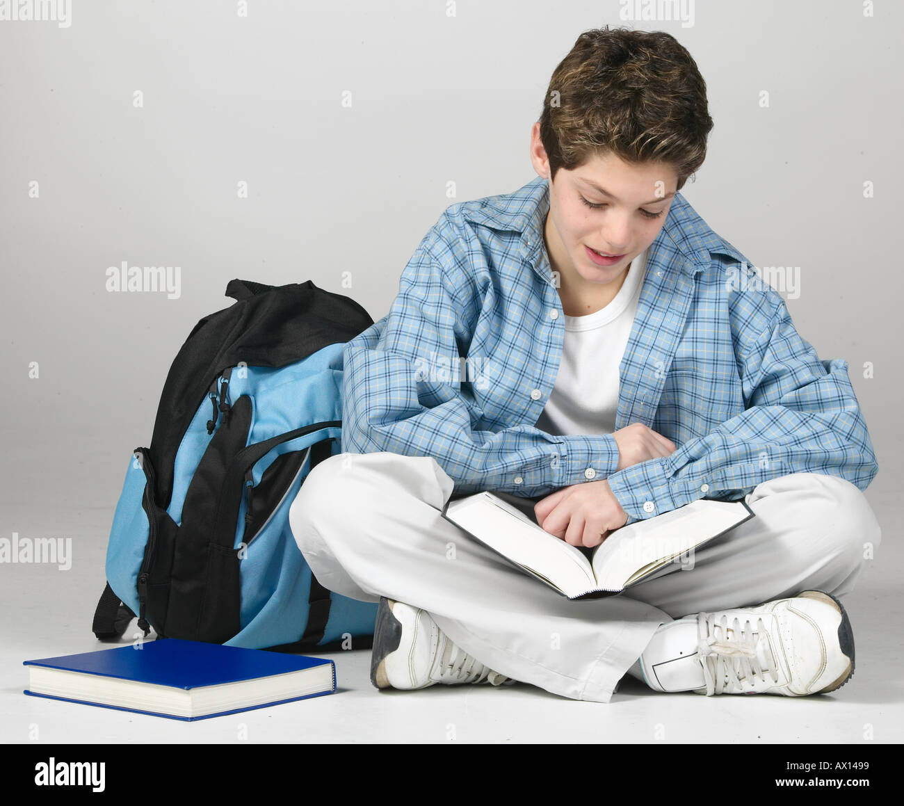 Smiling teenaged boy studying from textbook Stock Photo - Alamy