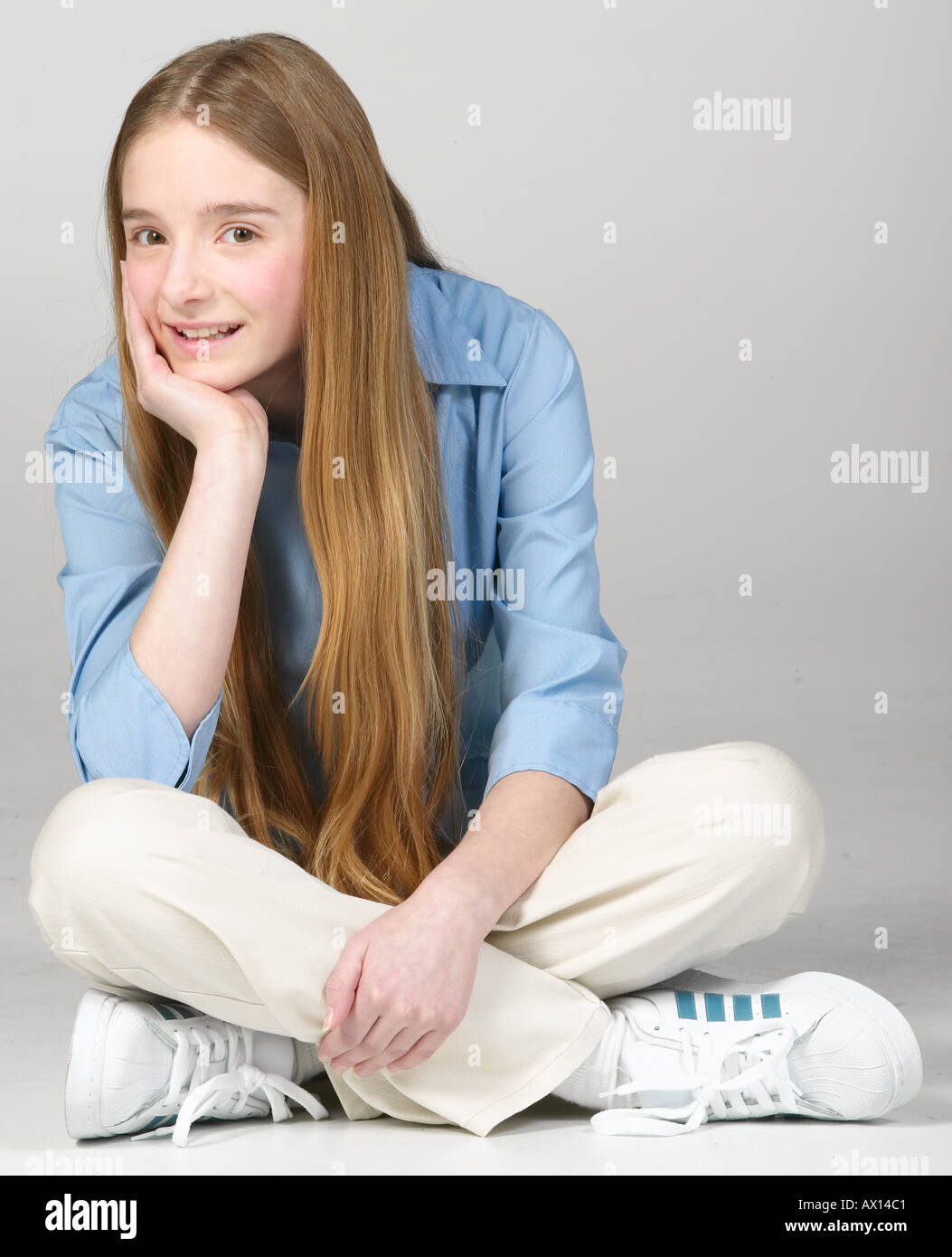 Smiling teenaged girl sitting cross legged Stock Photo - Alamy