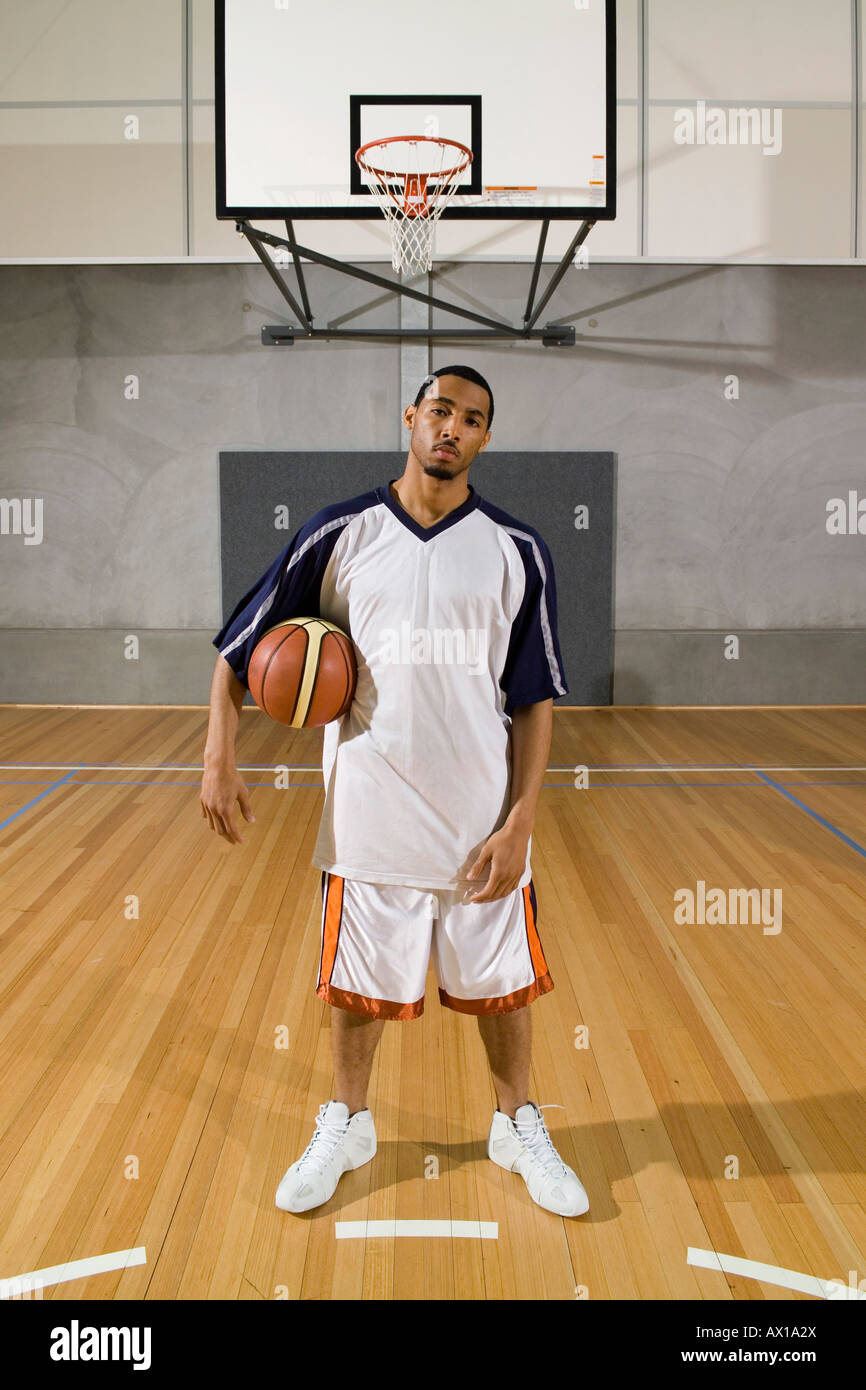 A young man standing on a basketball court with a basketball Stock ...