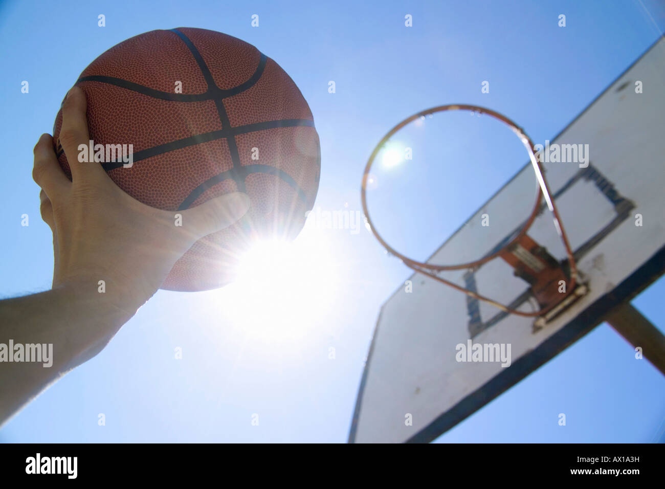 A human hand reaching up towards the sun and basketball hoop with ...