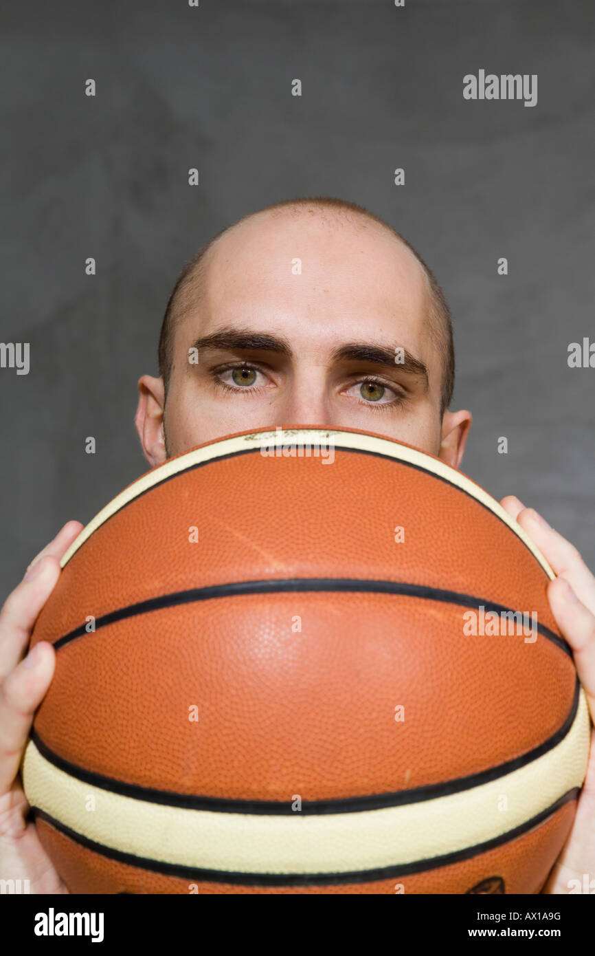 A young man with a basketball partially obscuring his face Stock Photo ...