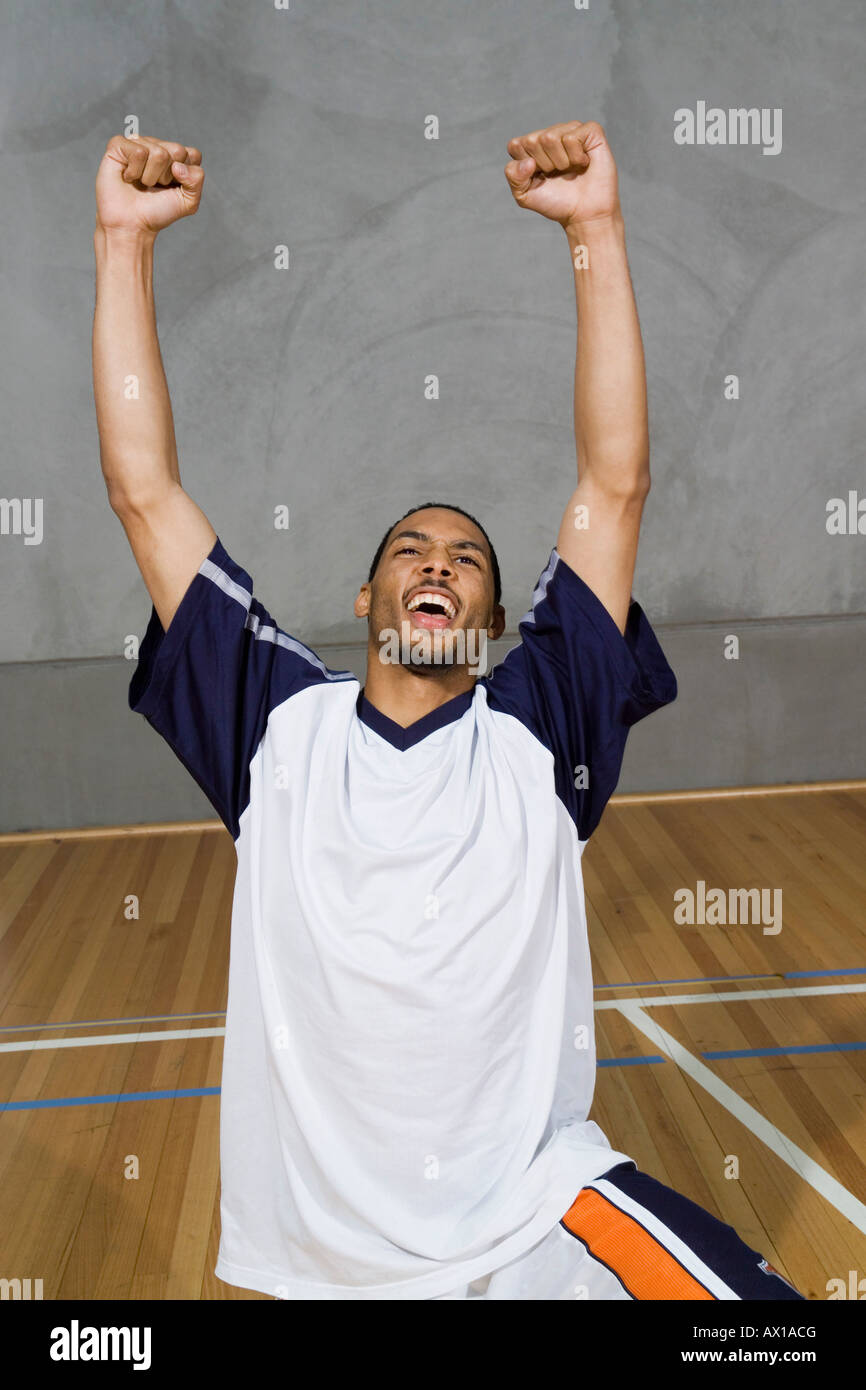 A young man kneeling with his arms raised in victory Stock Photo - Alamy