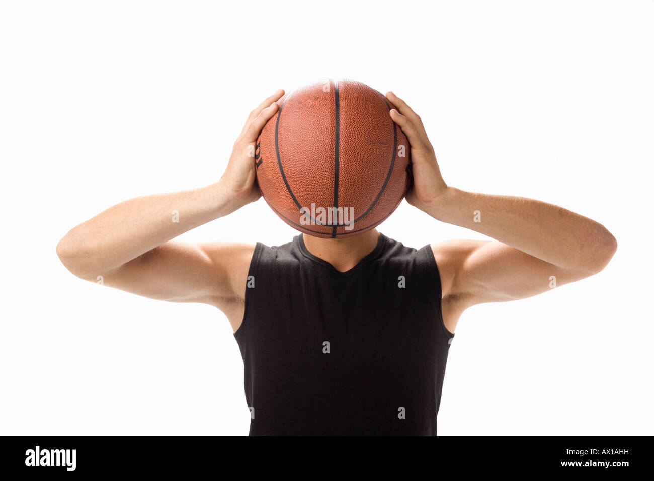 A studio portrait of a young man holding a basketball in front of his ...