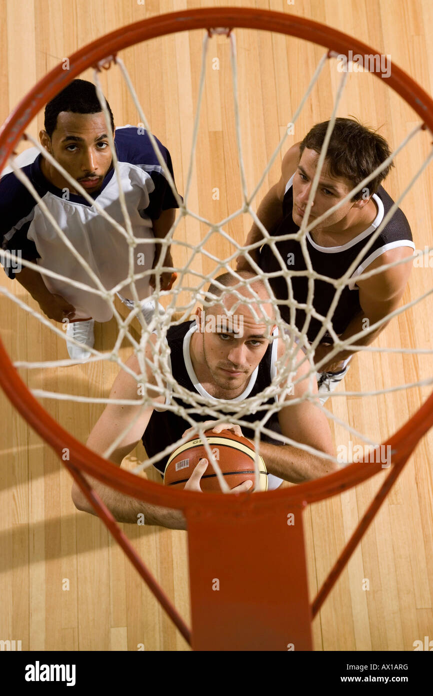Three basketball players standing below a basketball hoop Stock Photo ...