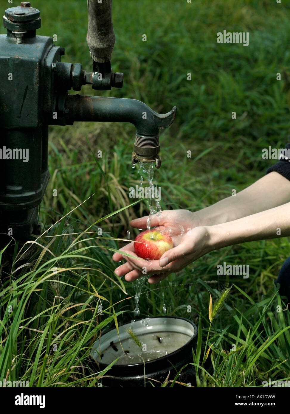 Washing an apple underneath an outdoor tap Stock Photo - Alamy