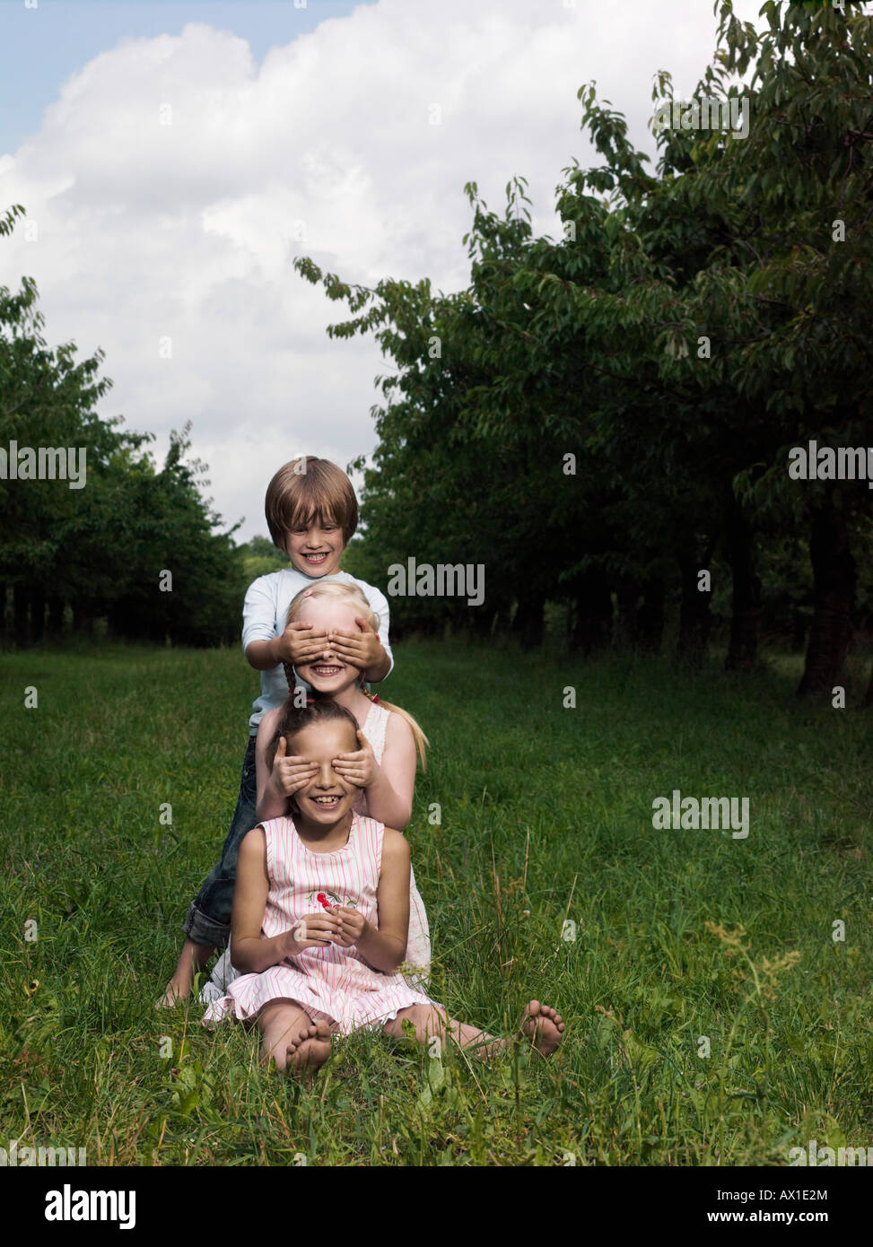 Three children playing in a field Stock Photo - Alamy