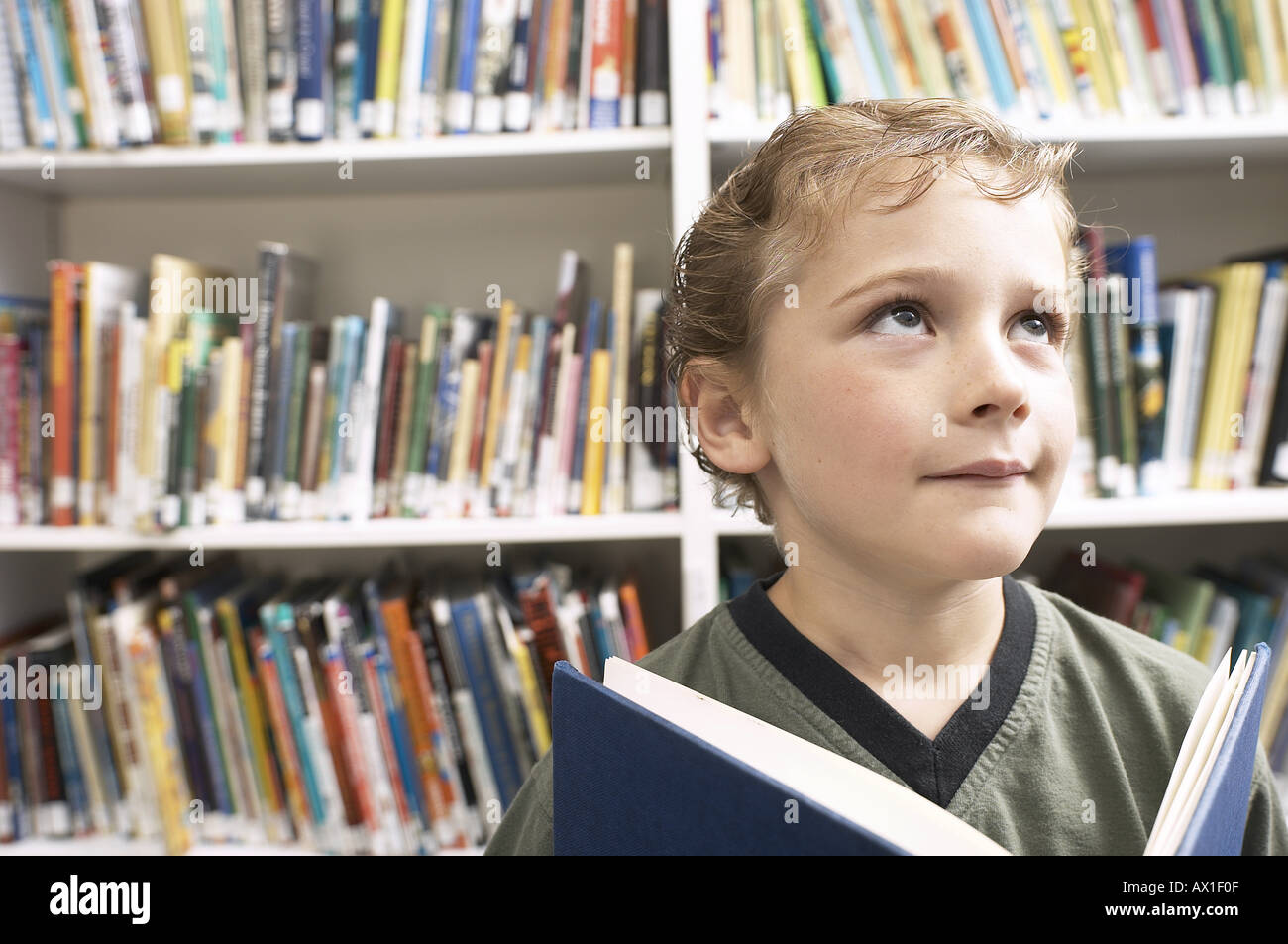 Little boy holding blue book in library 1 Stock Photo - Alamy