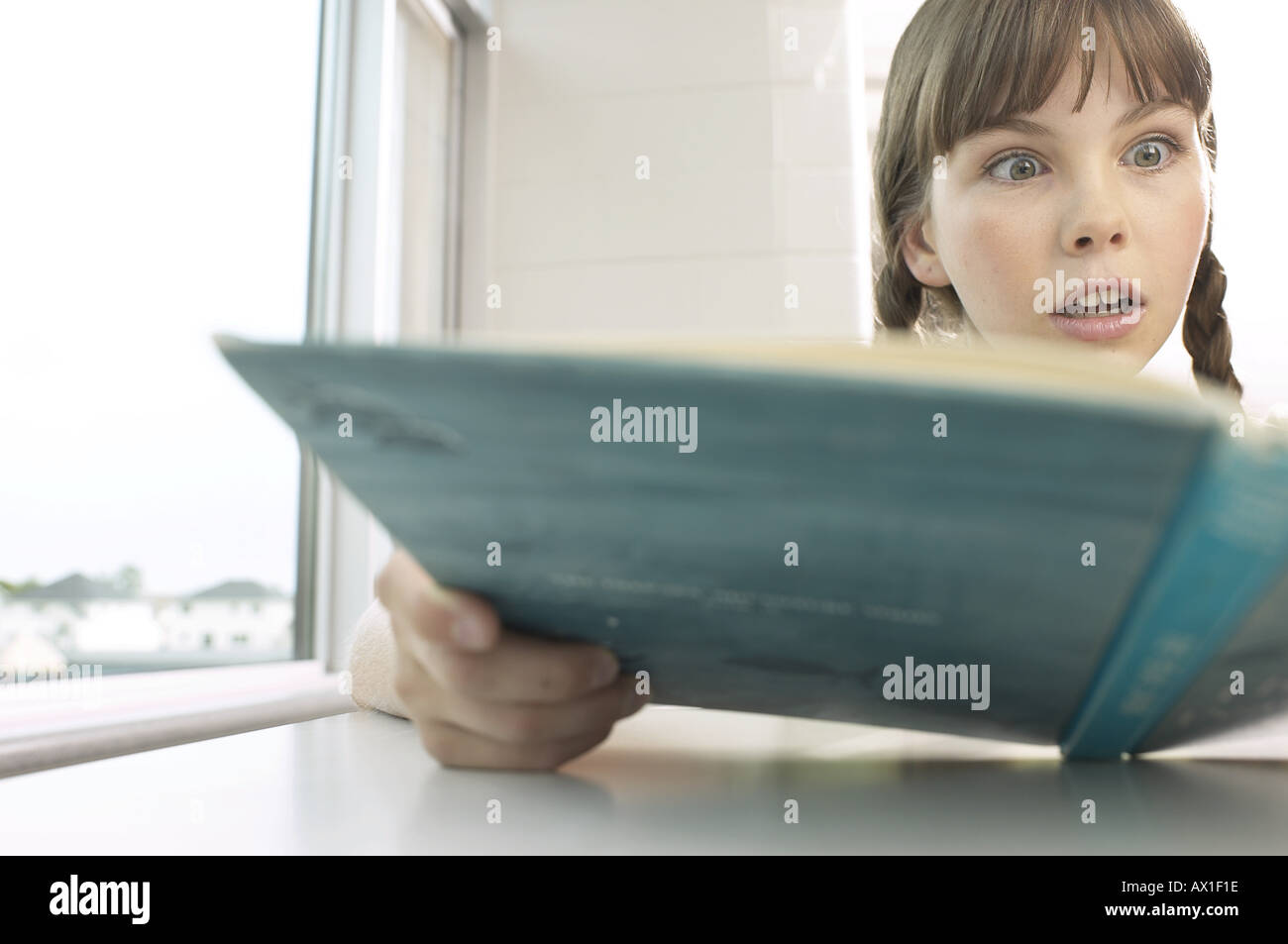 Amazed little girl reading book in classroom Stock Photo - Alamy
