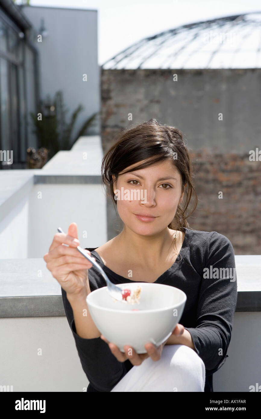 A woman eating breakfast on a roof terrace Stock Photo - Alamy