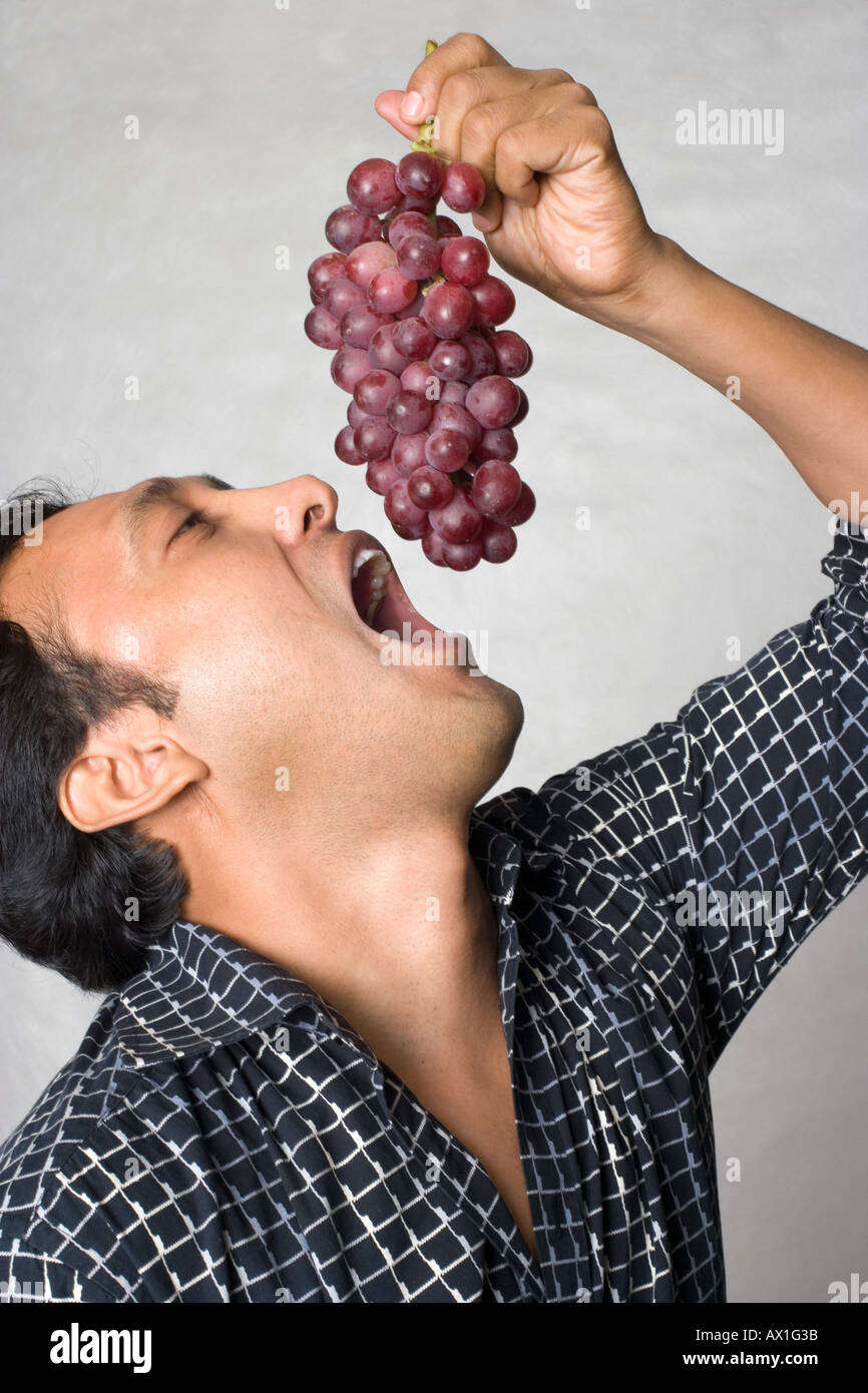Portrait Latino man eating grapes Stock Photo - Alamy