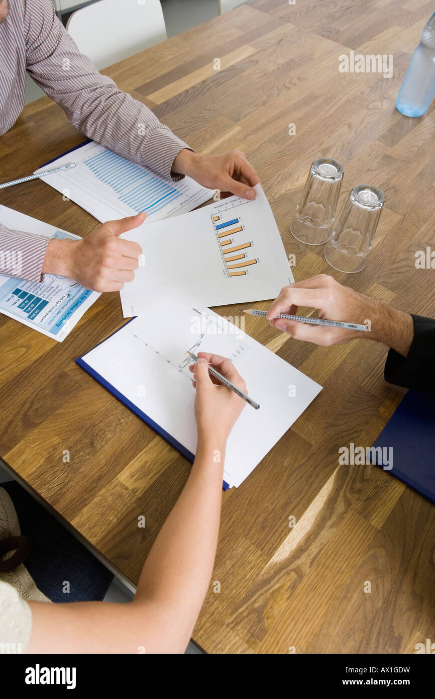 Detail of three people looking at documents in a business meeting Stock ...
