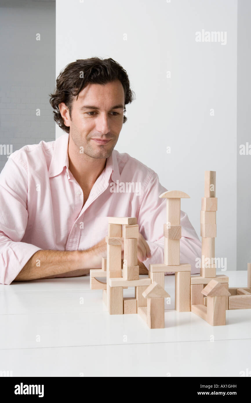 A man using wooden building blocks at a desk Stock Photo - Alamy