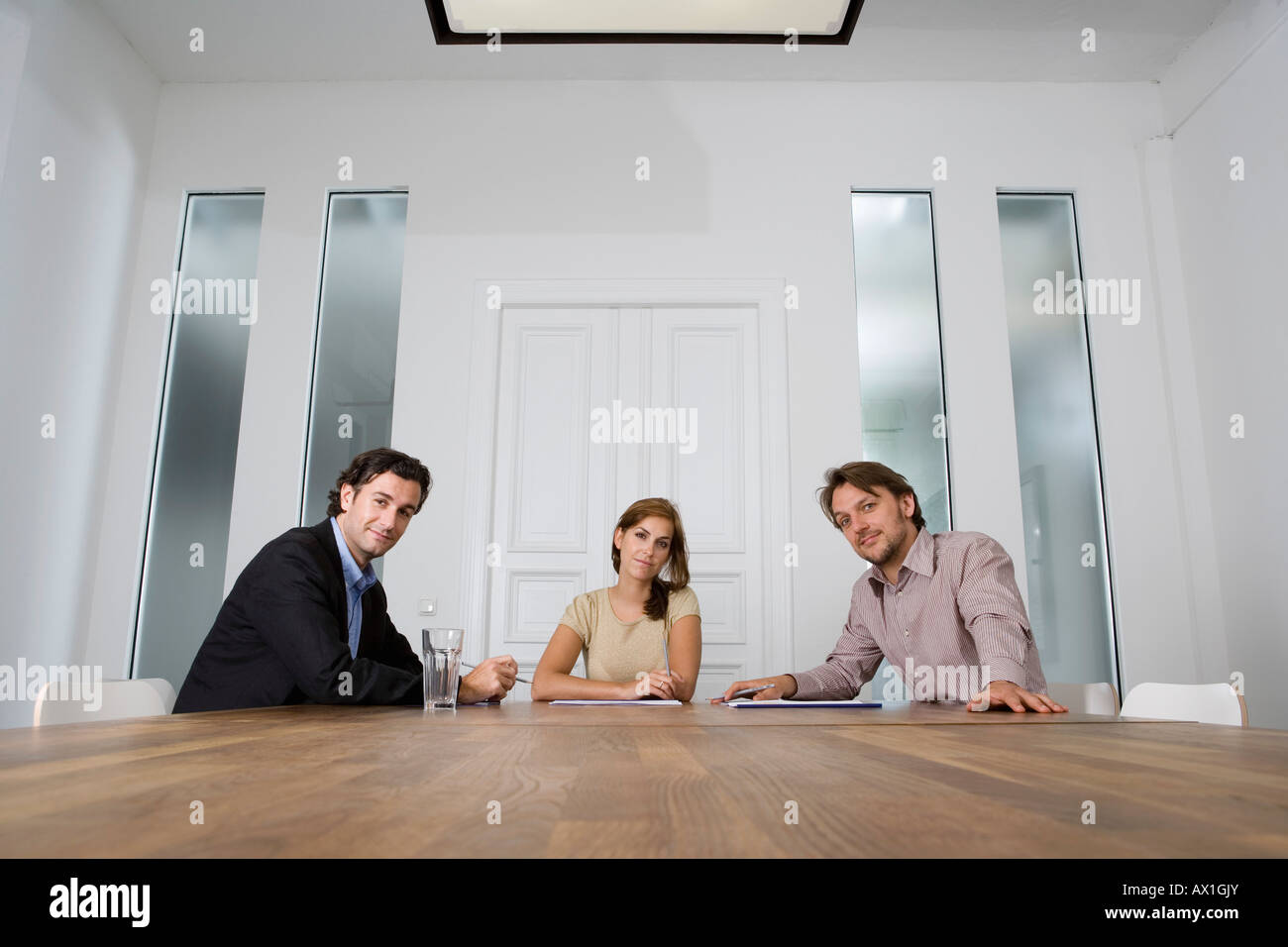 Three people sitting at a table in a conference room Stock Photo - Alamy