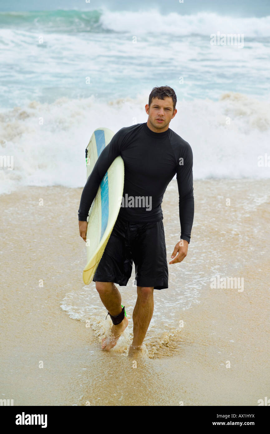 A surfer carrying his surfboard Stock Photo - Alamy