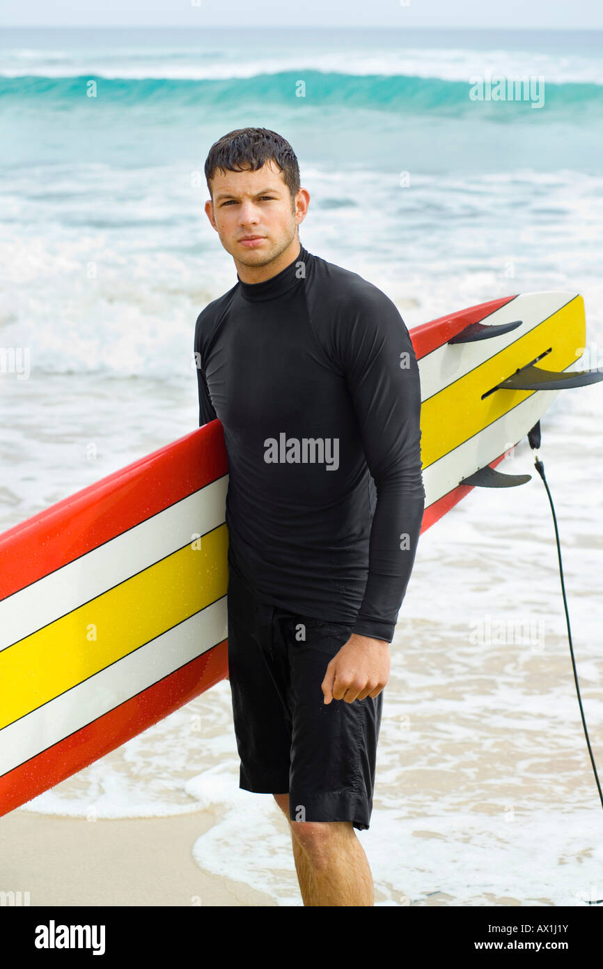 A surfer carrying his surfboard Stock Photo - Alamy