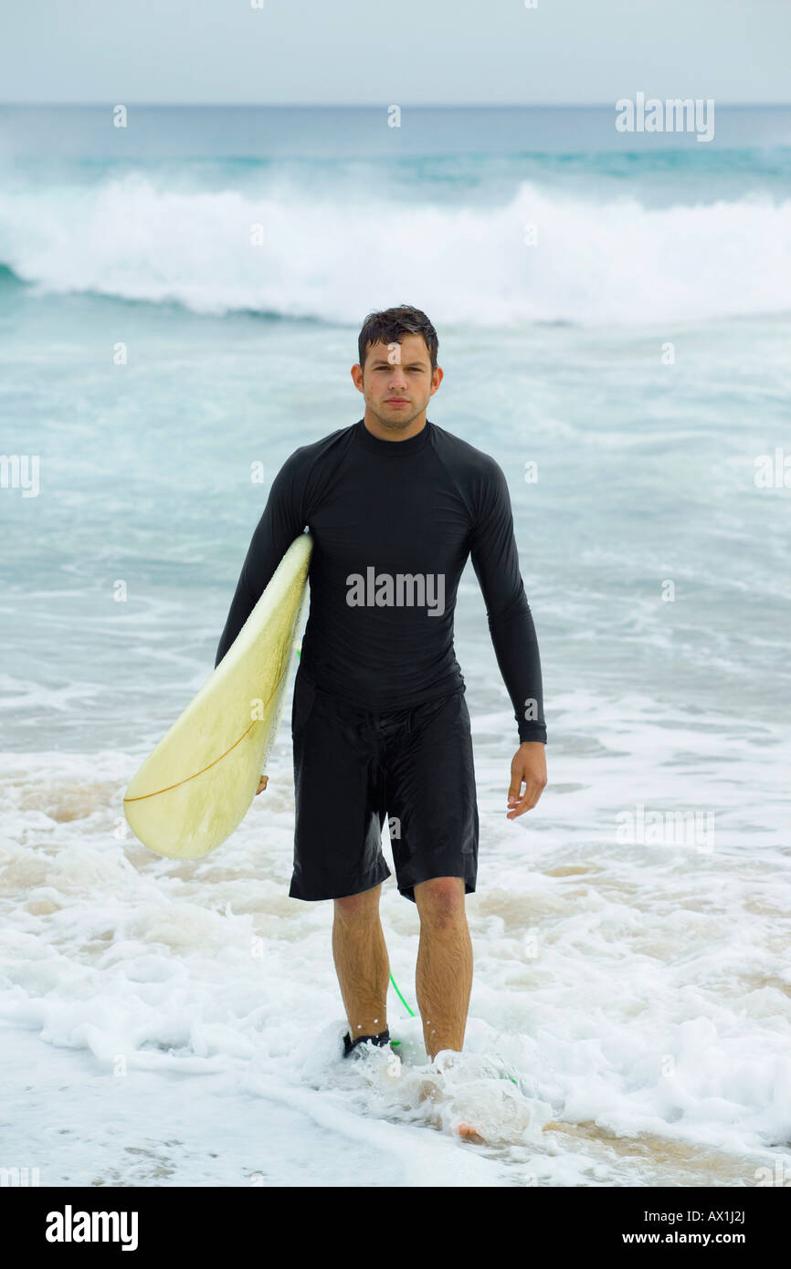 A surfer carrying his surfboard Stock Photo - Alamy