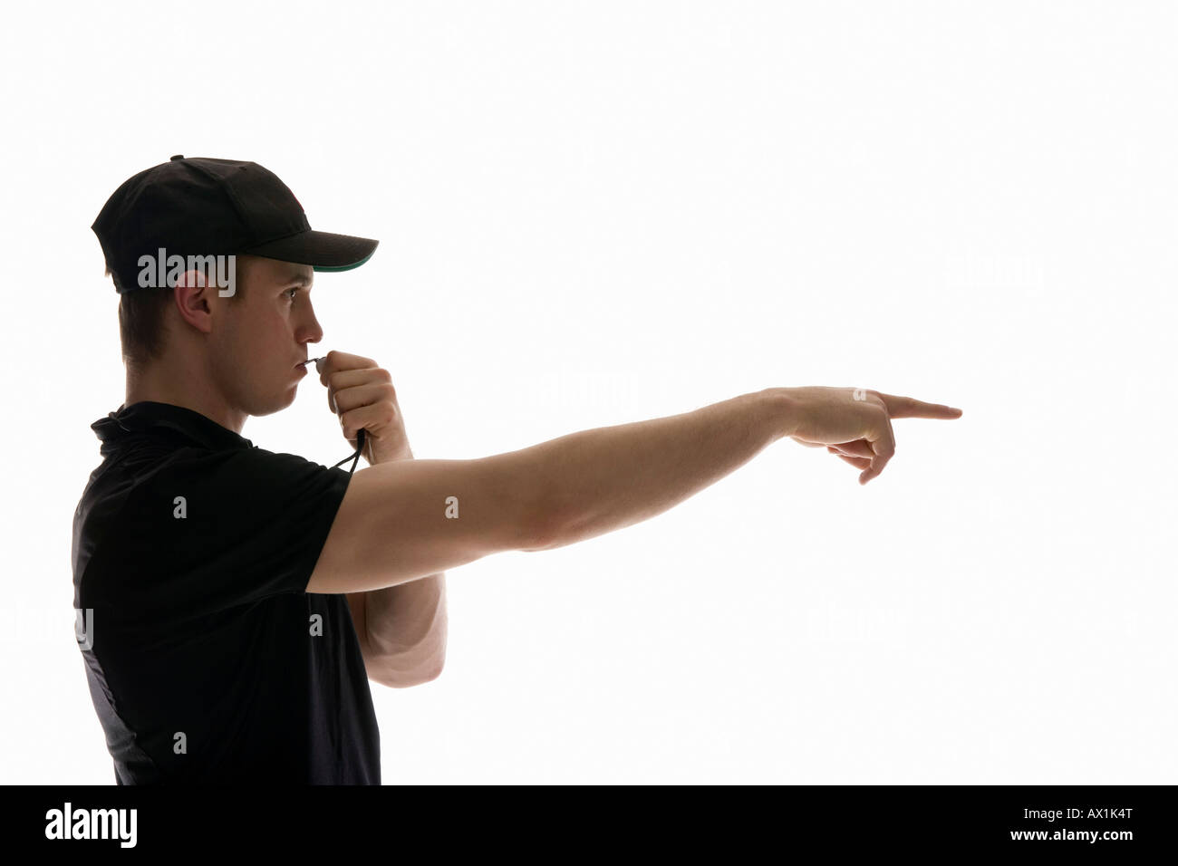 Side view studio portrait of a referee blowing a whistle and pointing ...