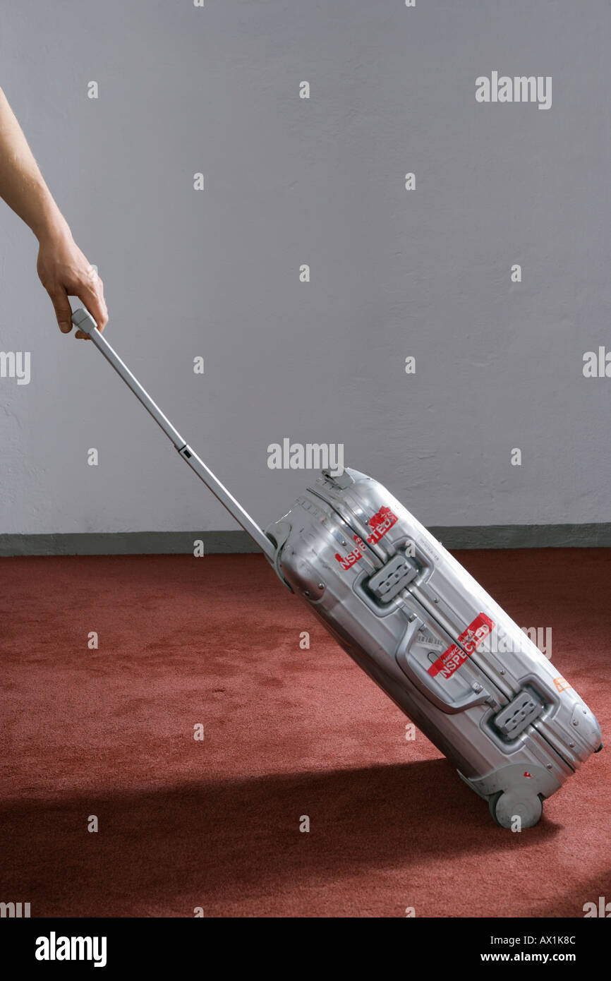 Man pulling rolling suitcase Stock Photo - Alamy