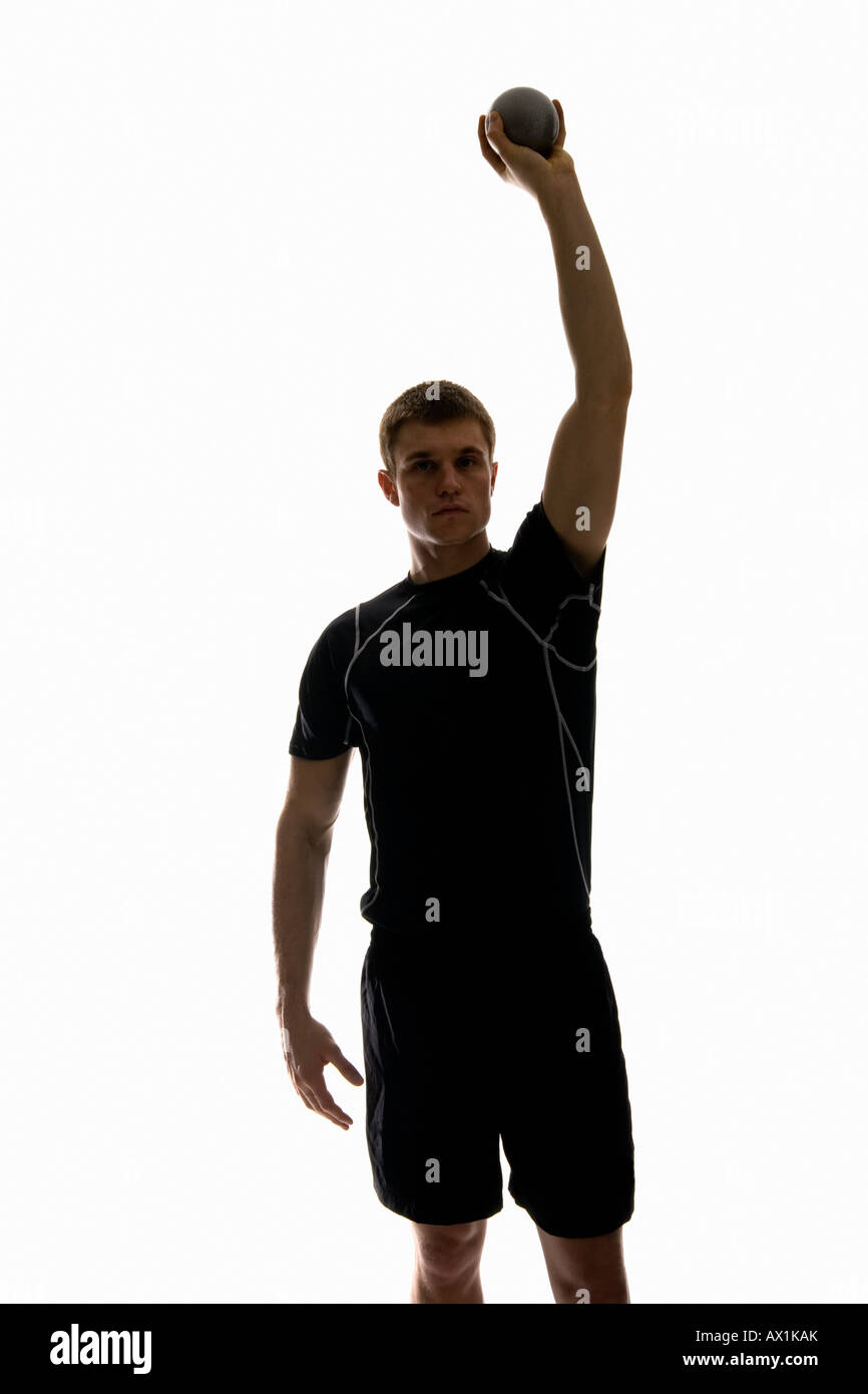 Studio shot of a male track and field athlete holding a shot put ball ...