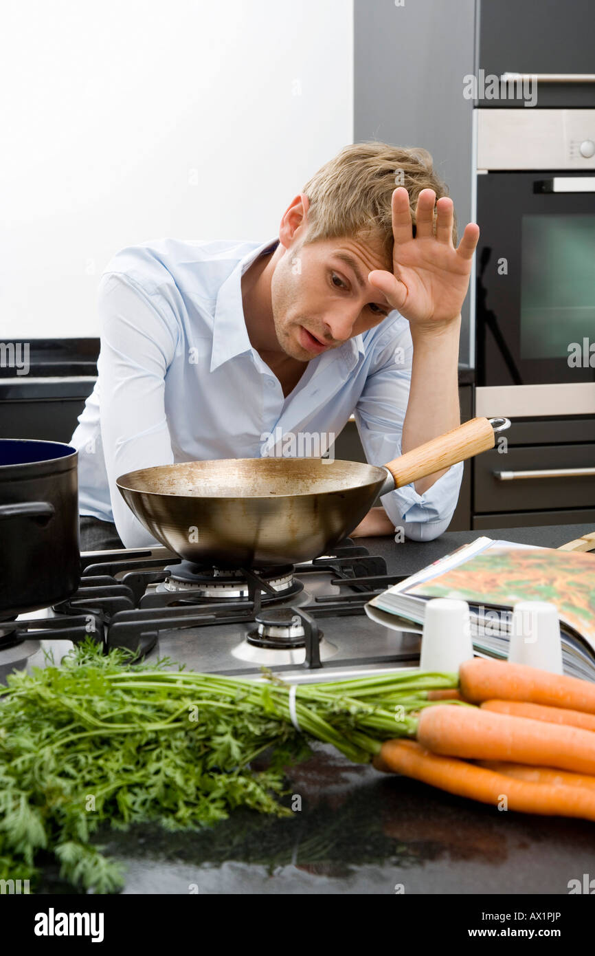 A man leaning over a pan and looking frustrated Stock Photo - Alamy