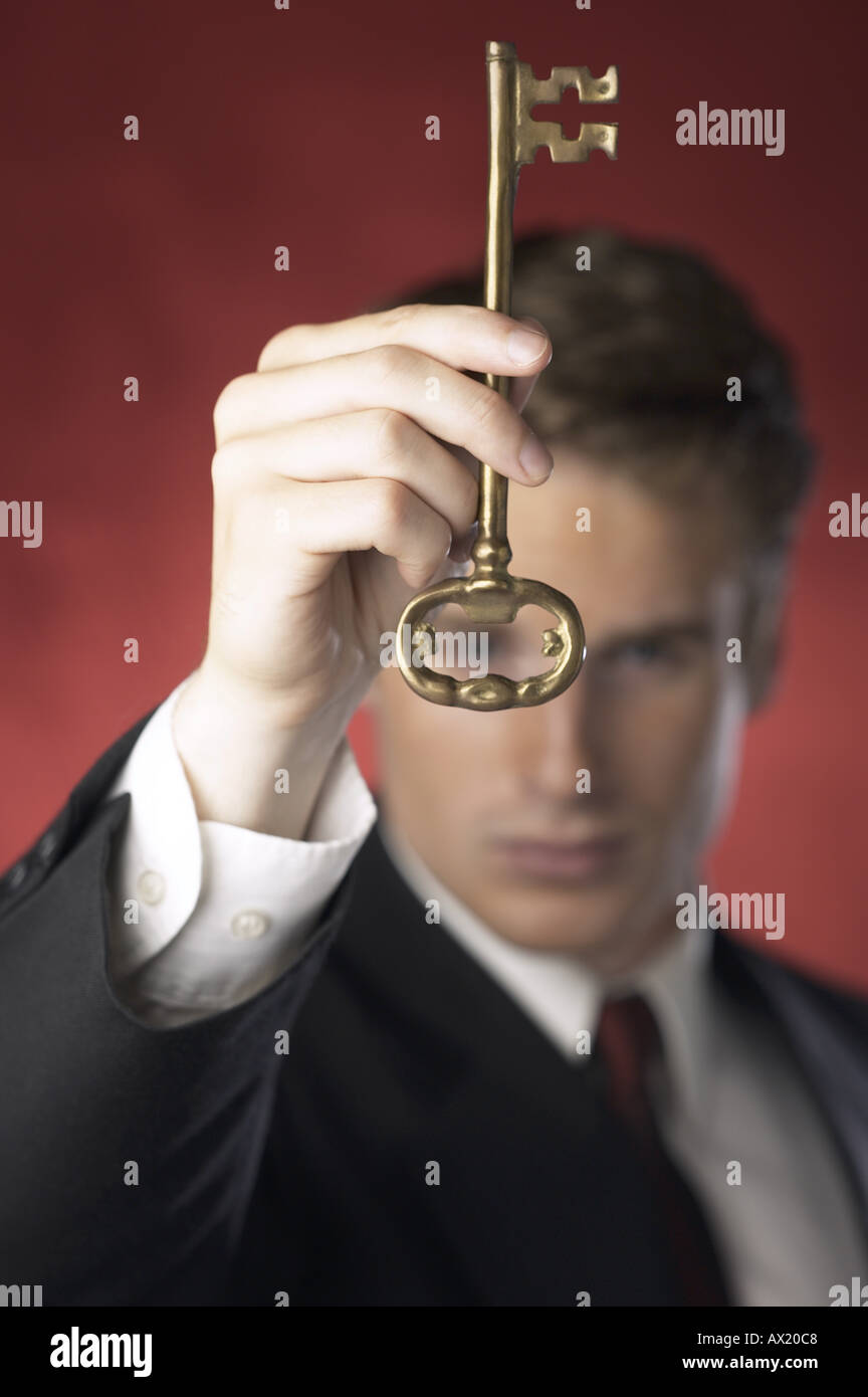 Man in suit holding antique key Stock Photo - Alamy
