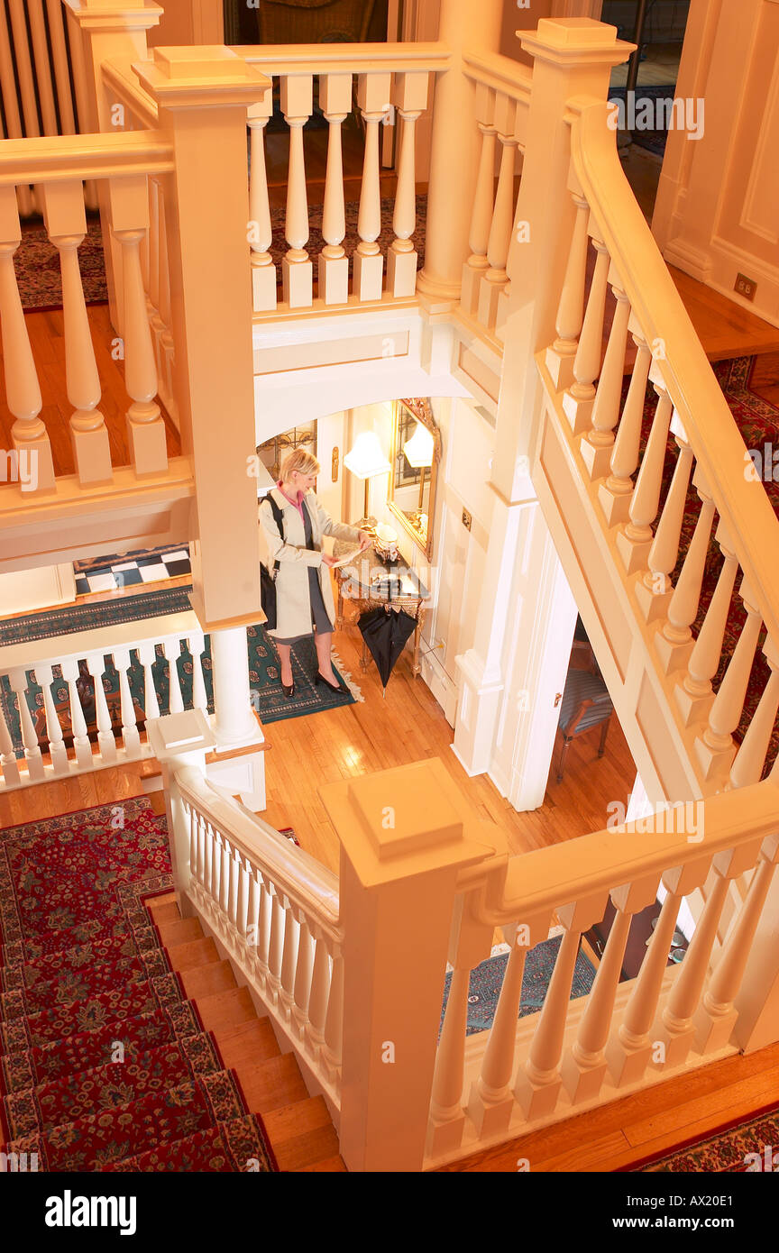 Woman in home at the bottom of staircase Stock Photo - Alamy