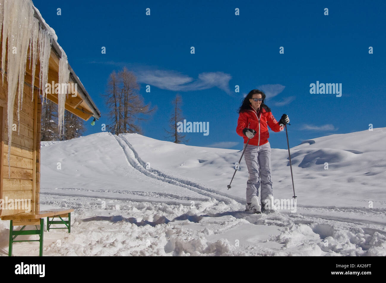 Woman skiing past icicles hanging from a cabin in Hinterstoder, Austria ...