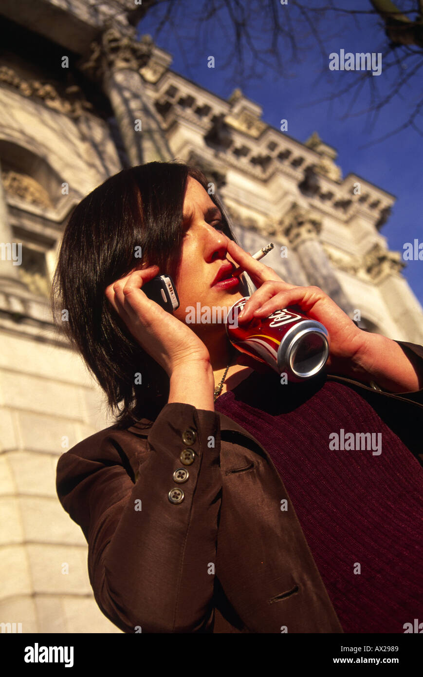 Stressed young woman smoking and drinking Coca Cola while talking on ...