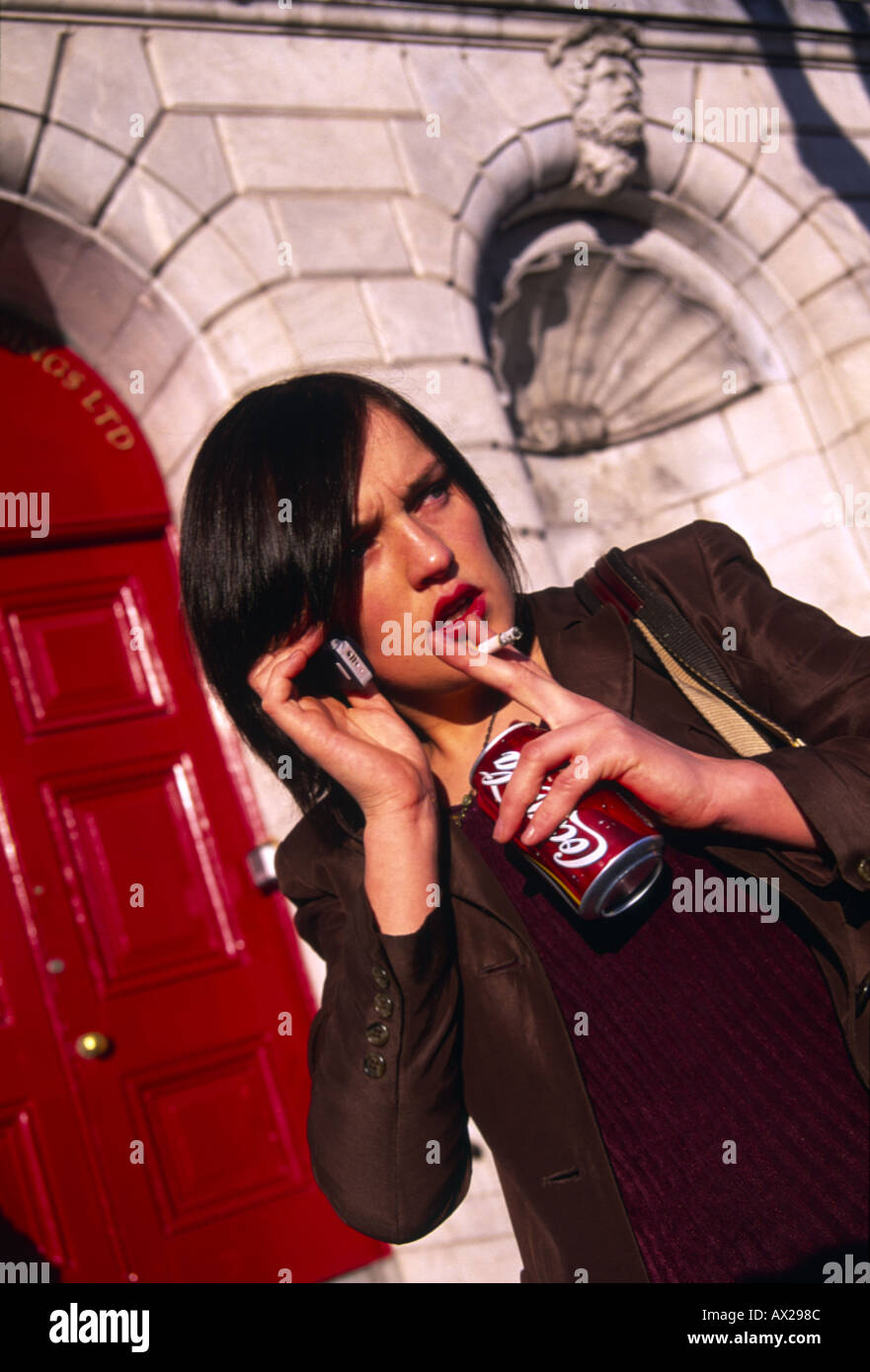 Stressed young woman smoking and drinking Coca Cola while talking on ...