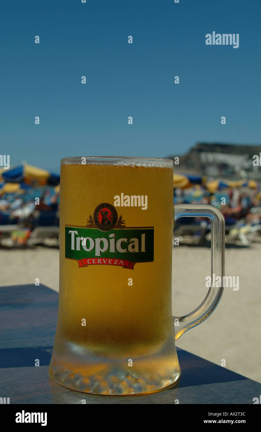 A cold crisp pint of lager with a hot beach background with a clear ...