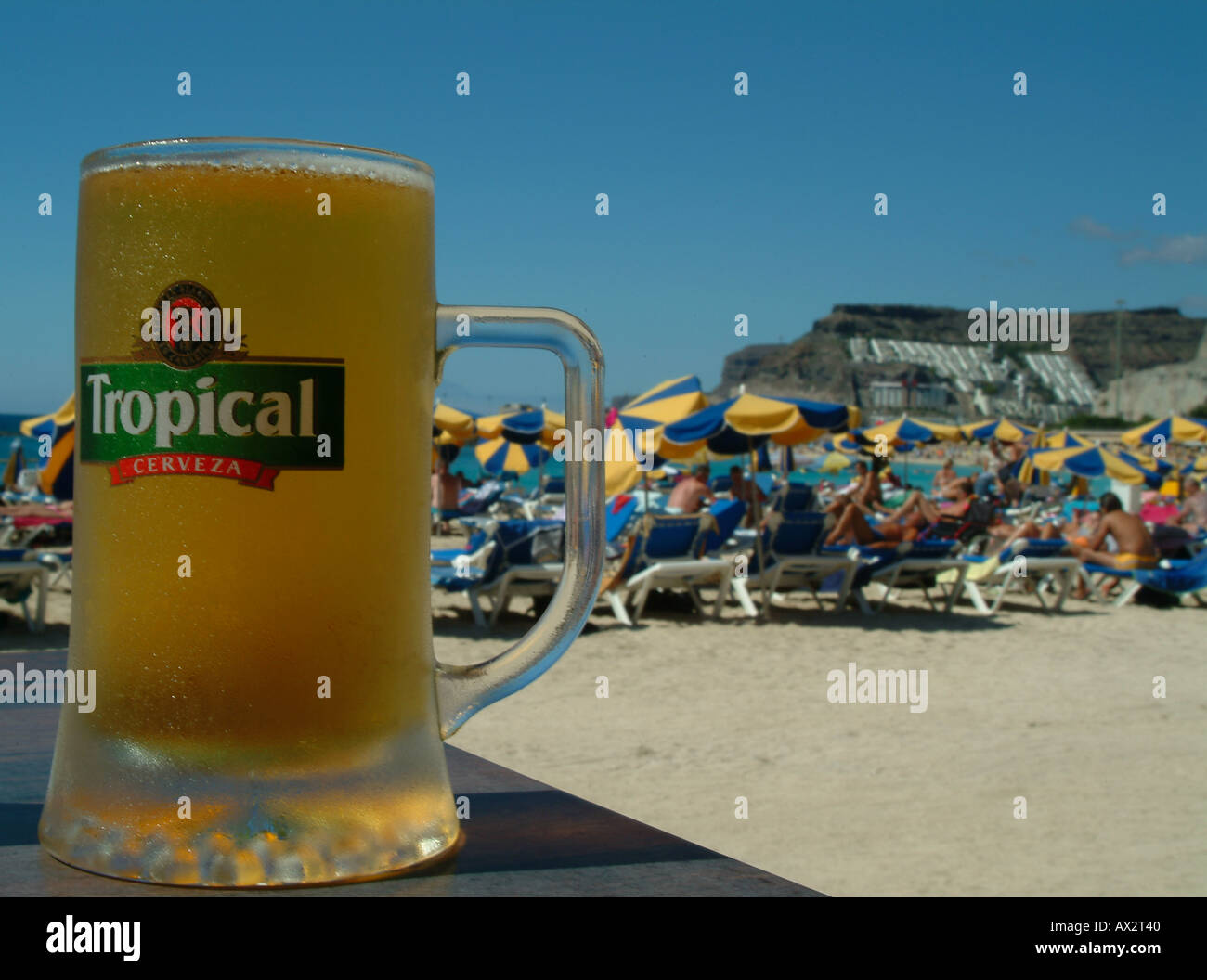 A cold crisp pint of lager with a hot beach background with a clear ...
