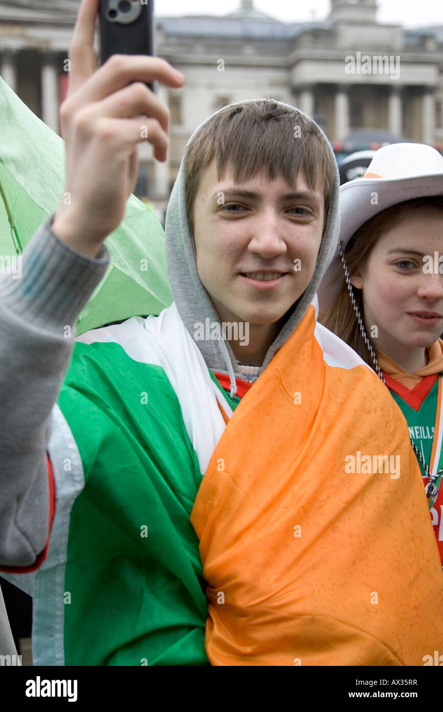 A young Irish boy with a flag draped over his shoulders singing at ...