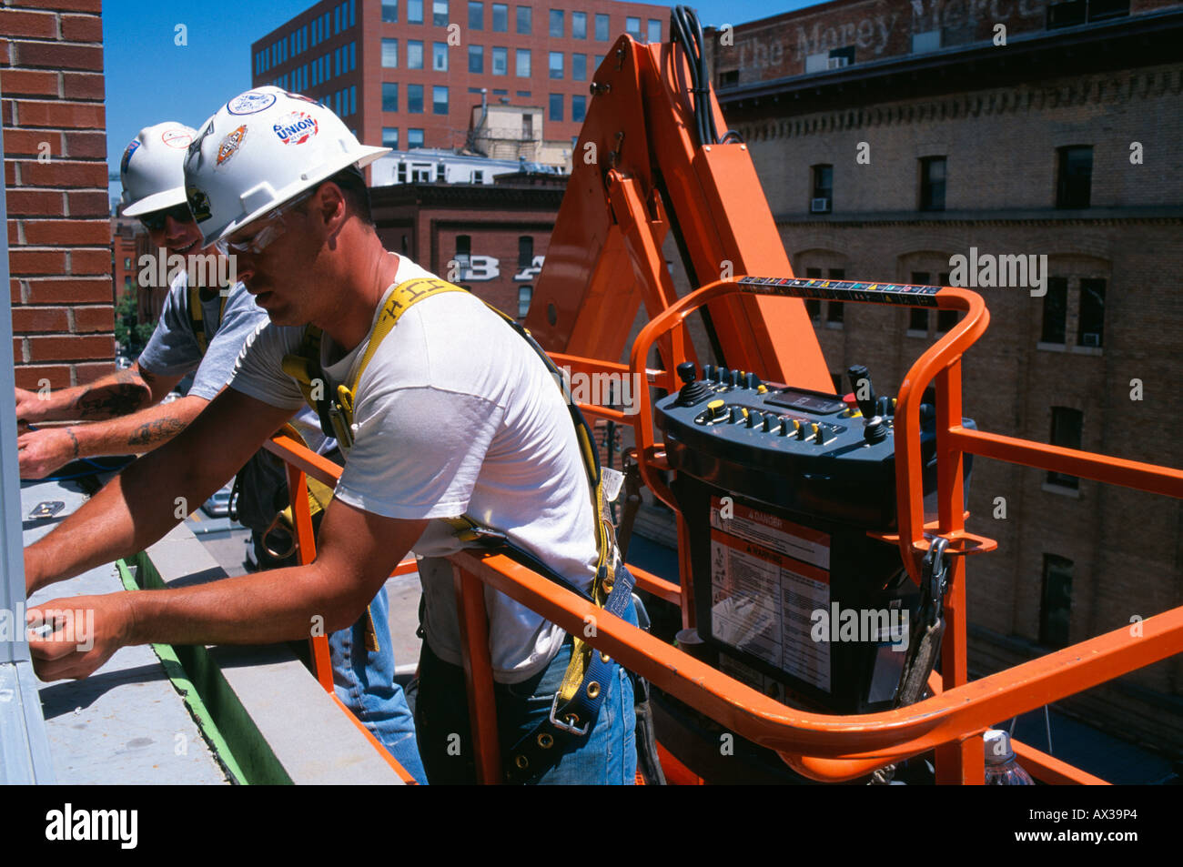 Construction workers in cherry picker installing windows in high rise ...