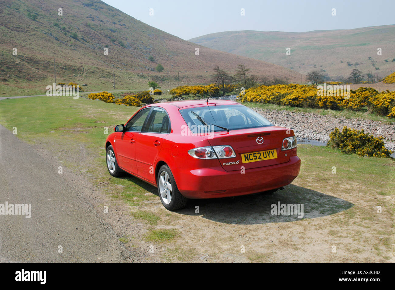 Rear view of a red Mazda 6 saloon car parked at the side of the road in ...