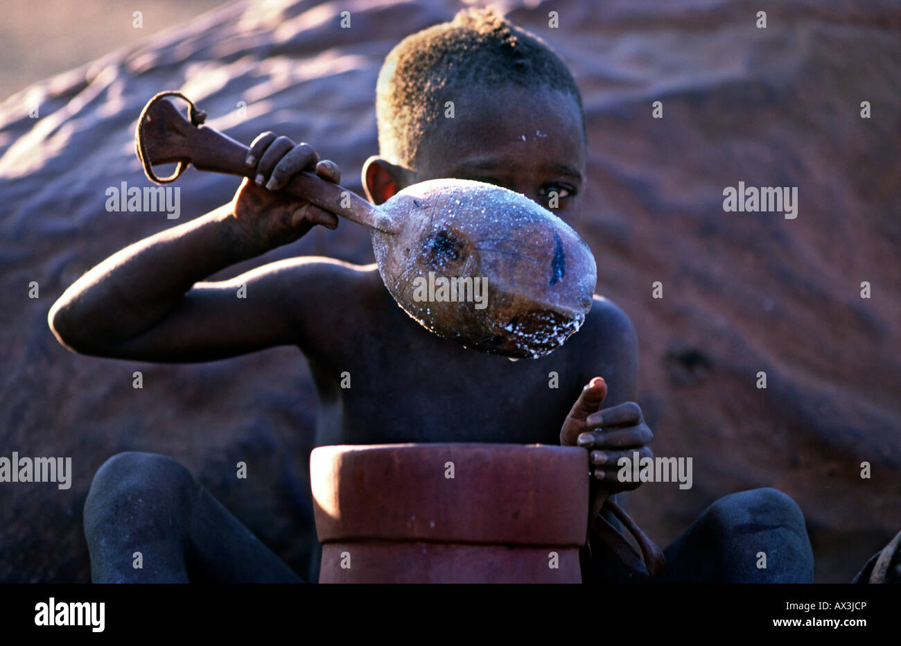 Himba boy enjoying a scoop of sour milk from kalabash Kaokoland Kunene ...