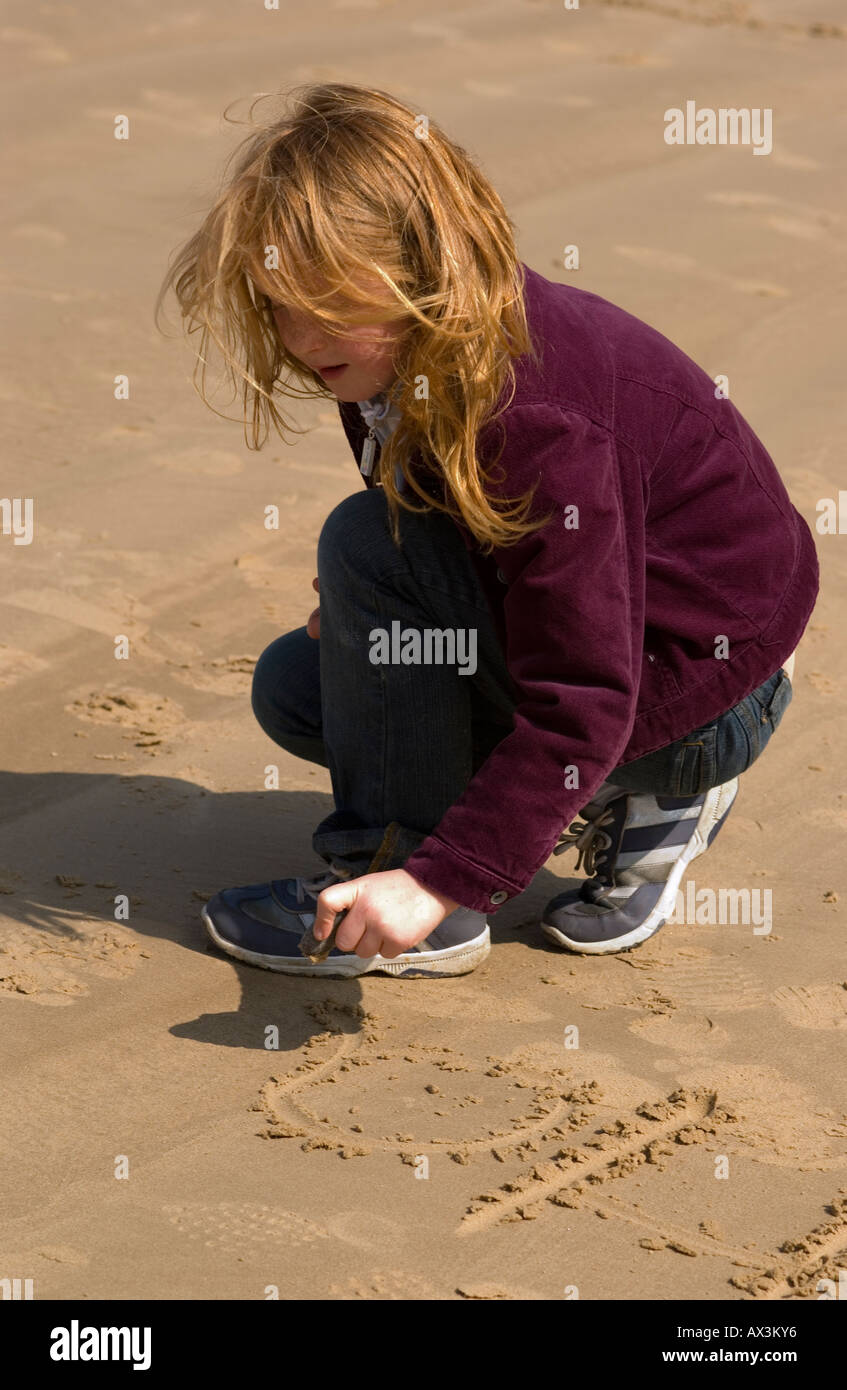 Young girl writing her name in the sand on a beach Stock Photo - Alamy