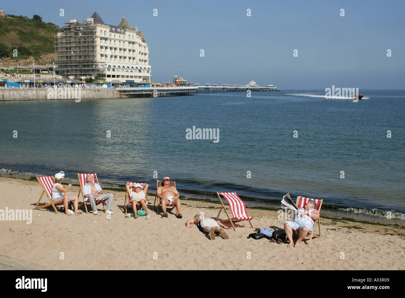 Old age pensioners relaxing and sunbathing on the beach in Llandudno ...