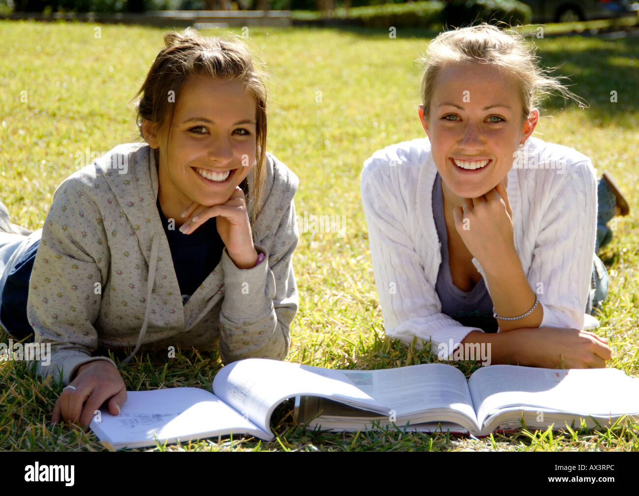 View of two young women reading books on a lawn Stock Photo - Alamy
