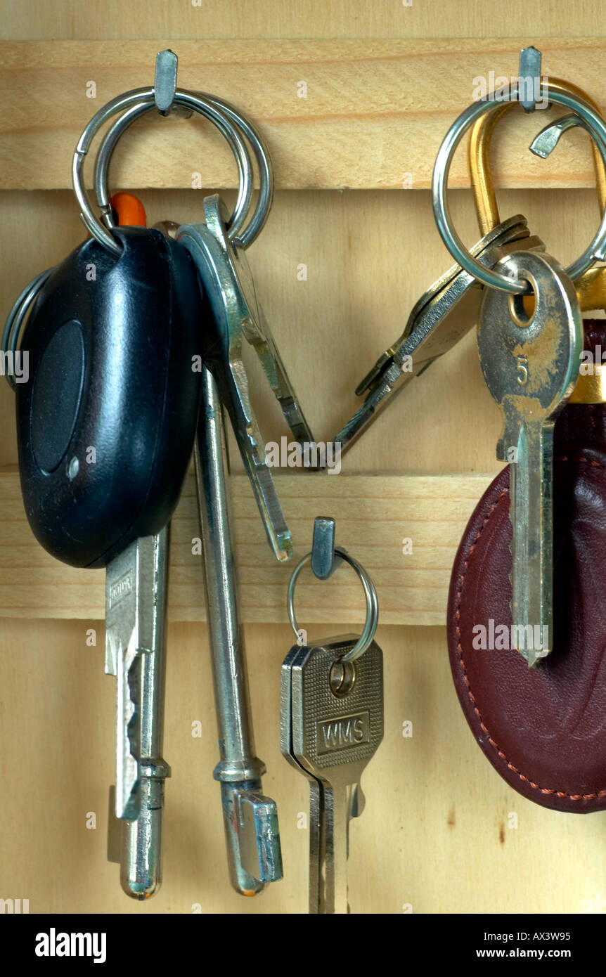 Keys on key rings and fobs hung on hooks in a key cupboard Stock Photo ...