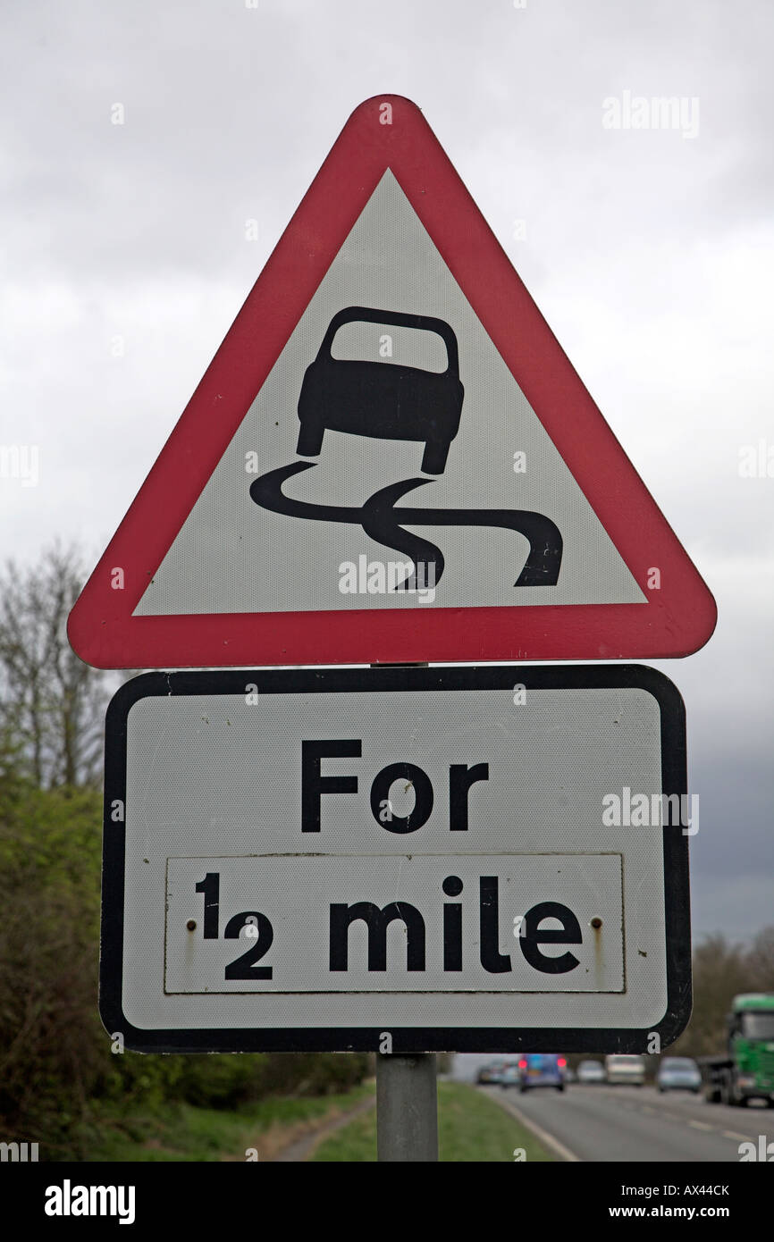 Red triangular road sign warning of slippery road ahead Stock Photo - Alamy