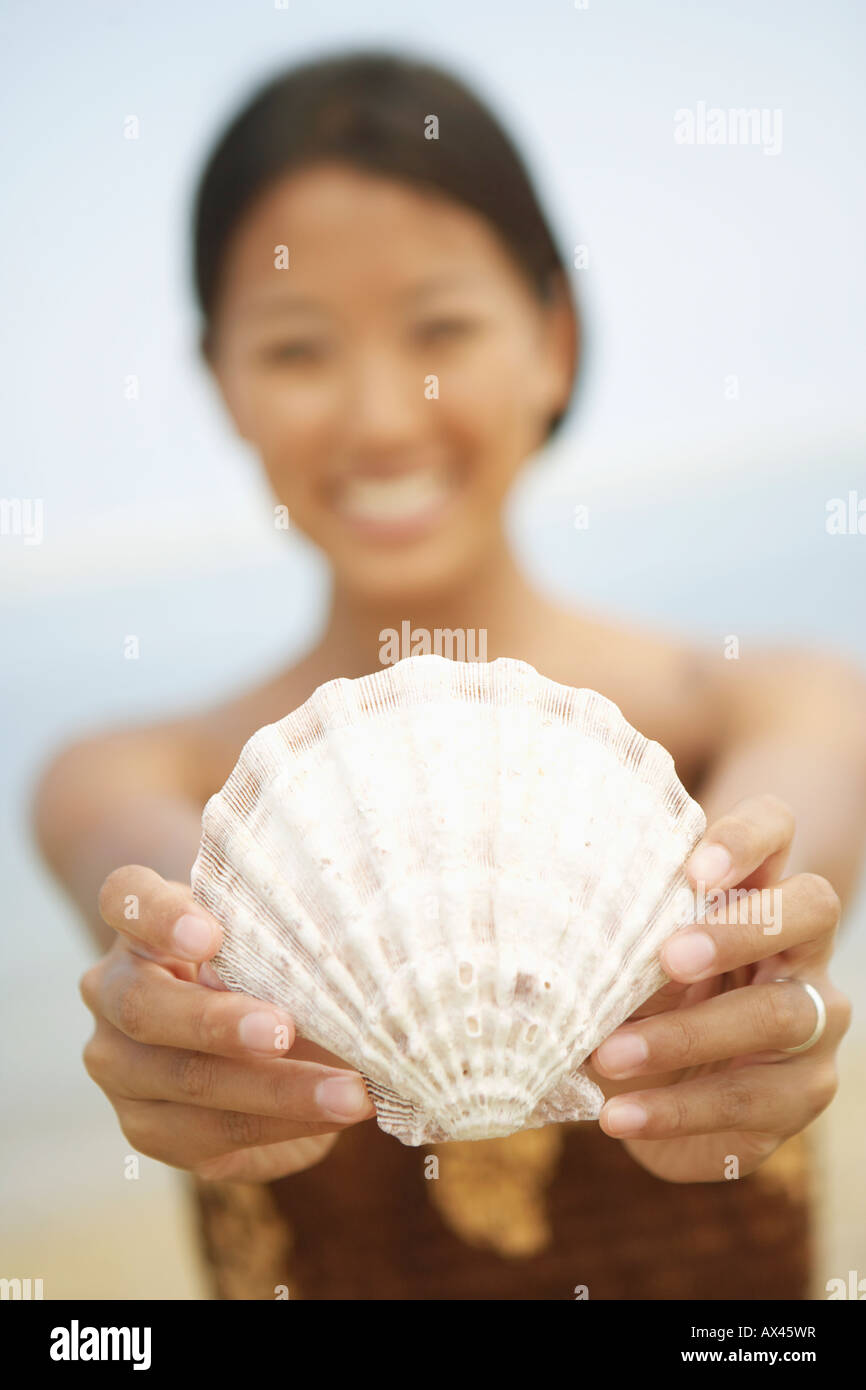 Asian woman holding out seashell Stock Photo - Alamy