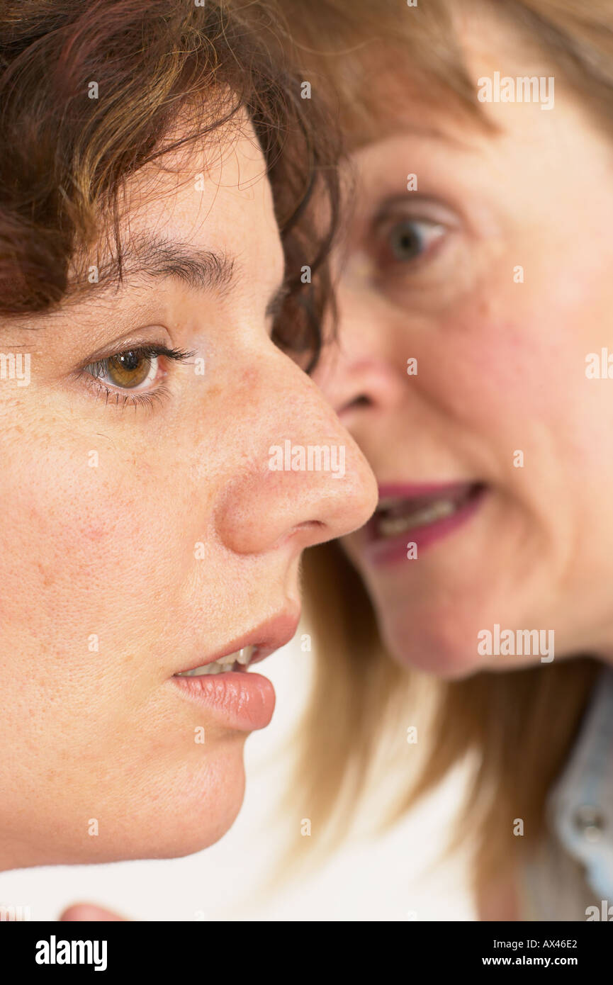 two women whisper a secret in close up of ear and mouth Stock Photo - Alamy