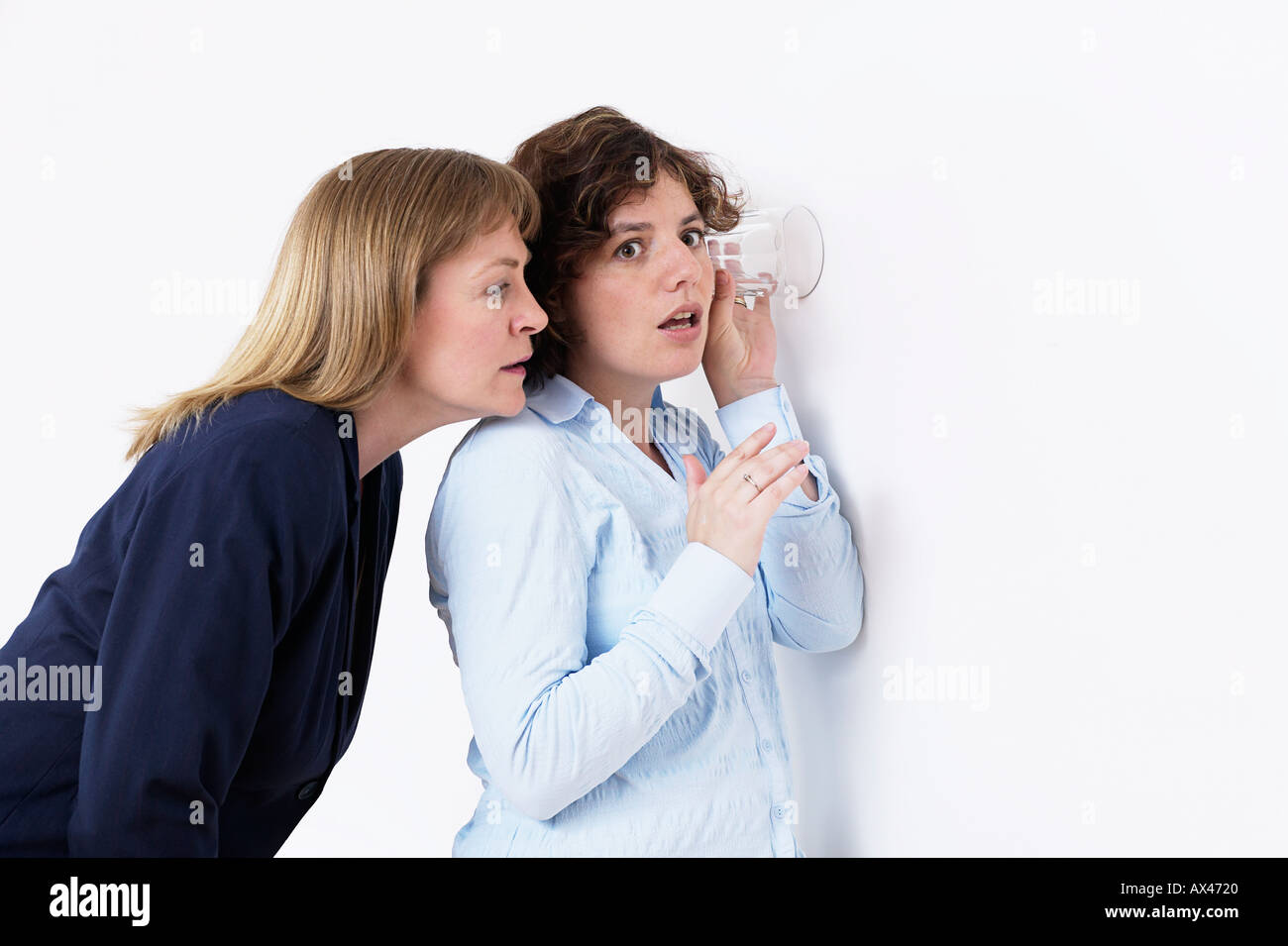 woman listening to conversation through wall with an ear to a glass ...