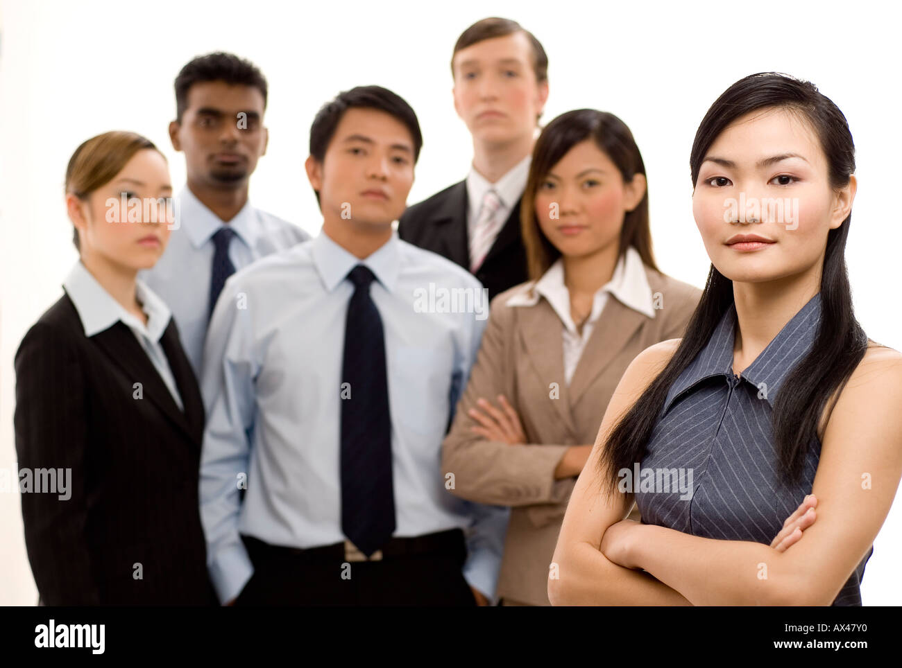 An attractive young asian team leader in focus stands in front of her ...