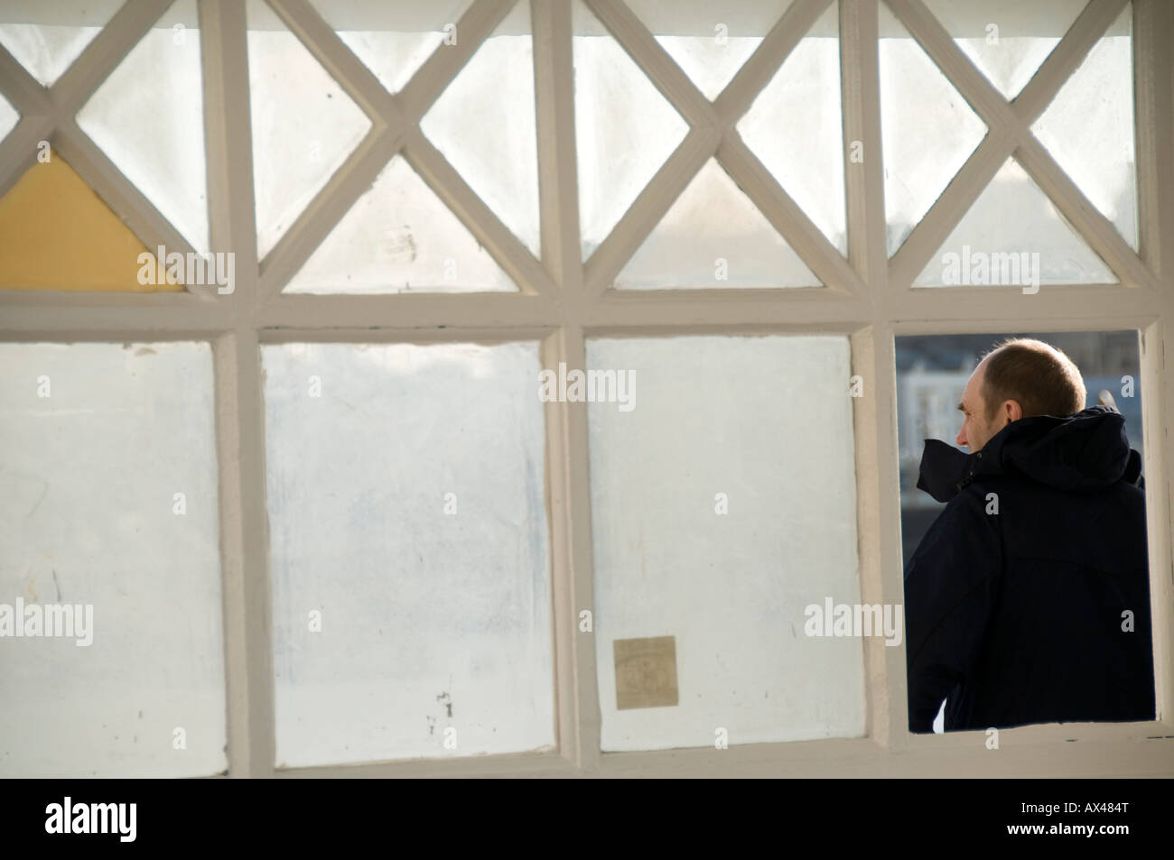 Man alone framed in broken window frame in public shelter on ...