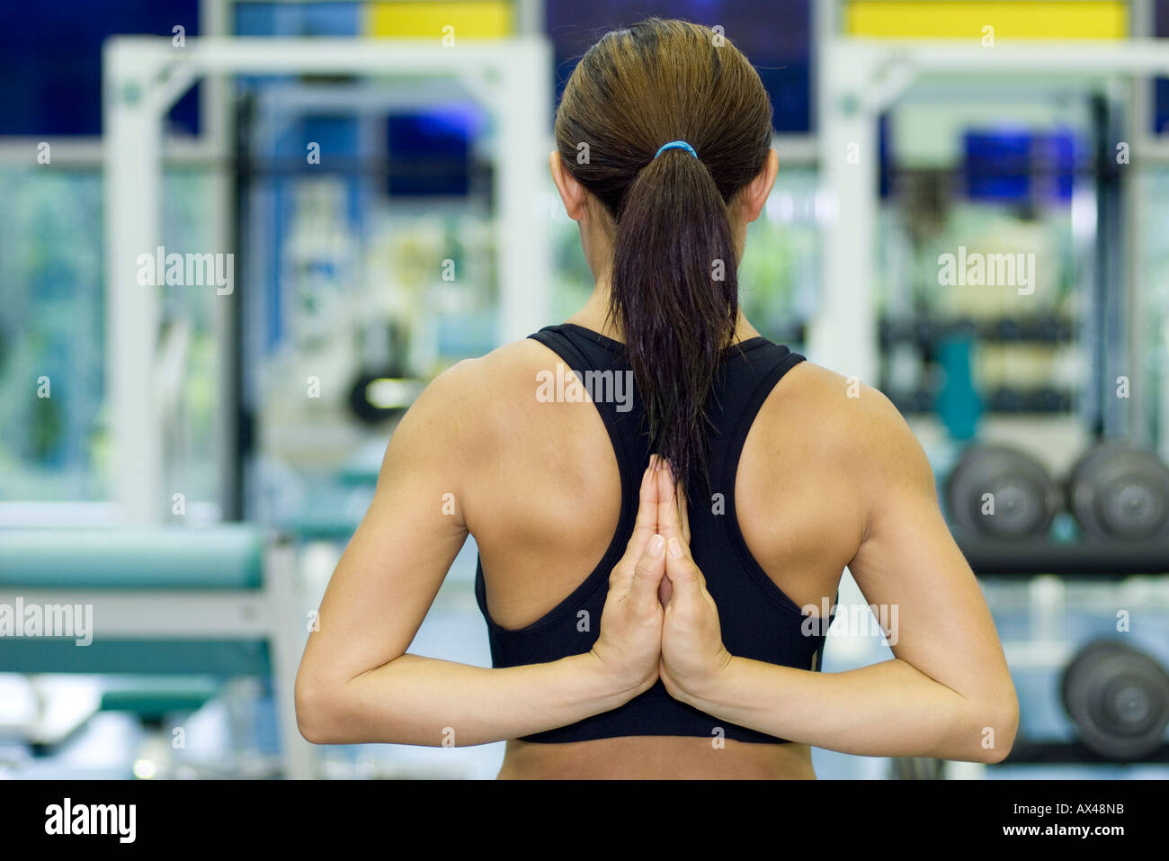 A female fitness instructor stretches her arms in a yoga pose in a gym ...