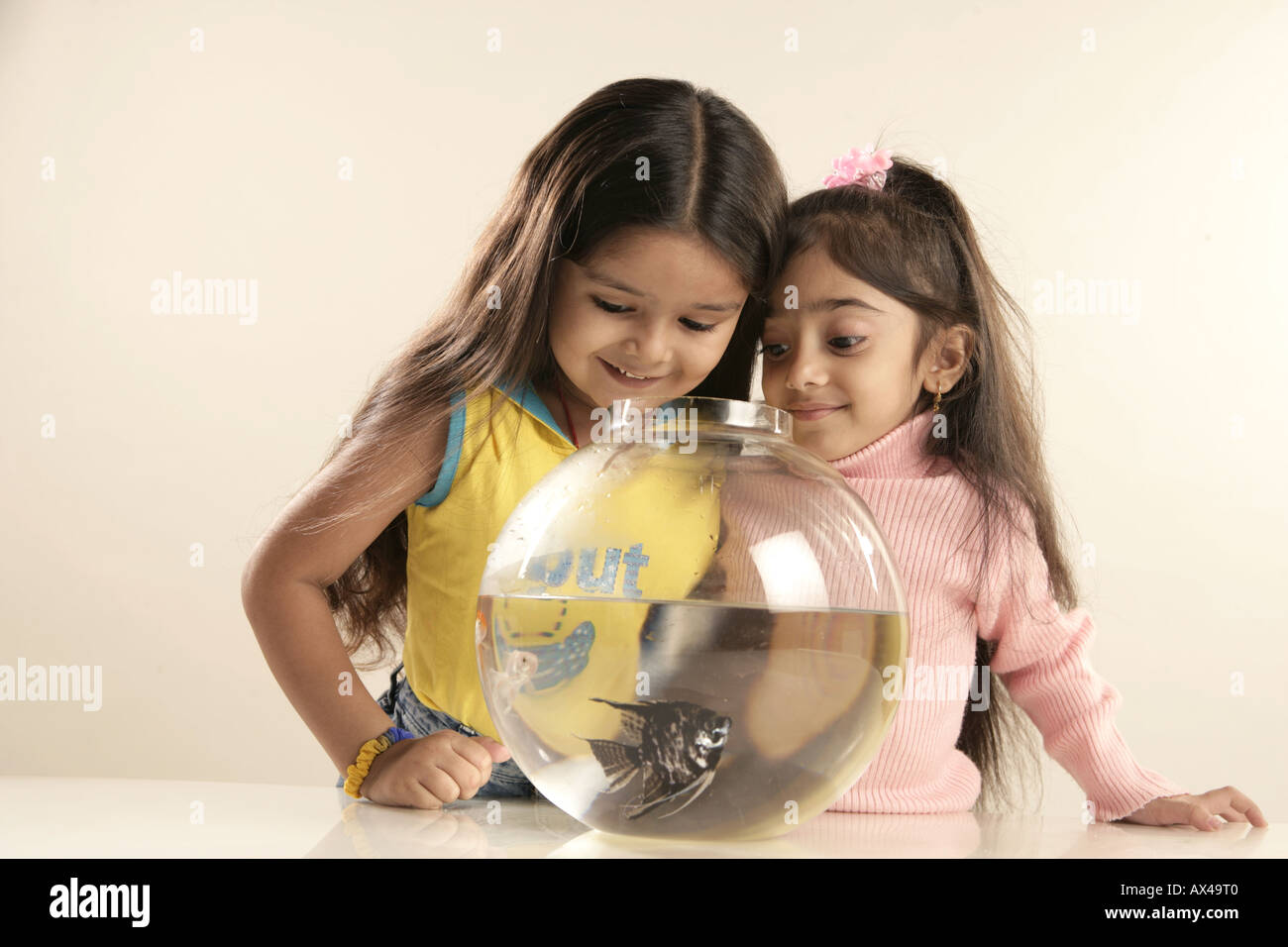 Two girls watching fish in a fishbowl Stock Photo - Alamy