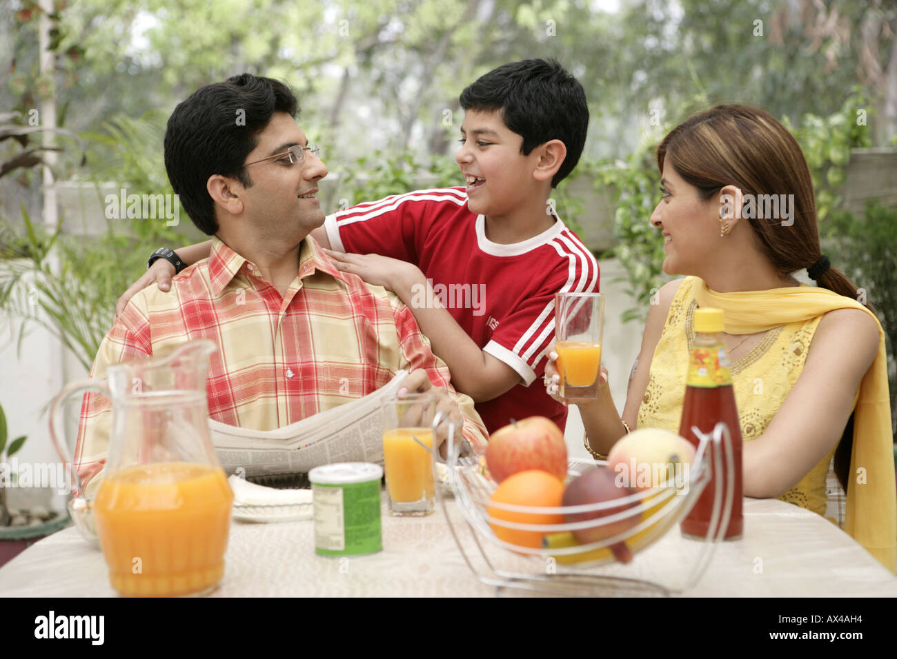 Family sitting at a dining table and smiling Stock Photo - Alamy